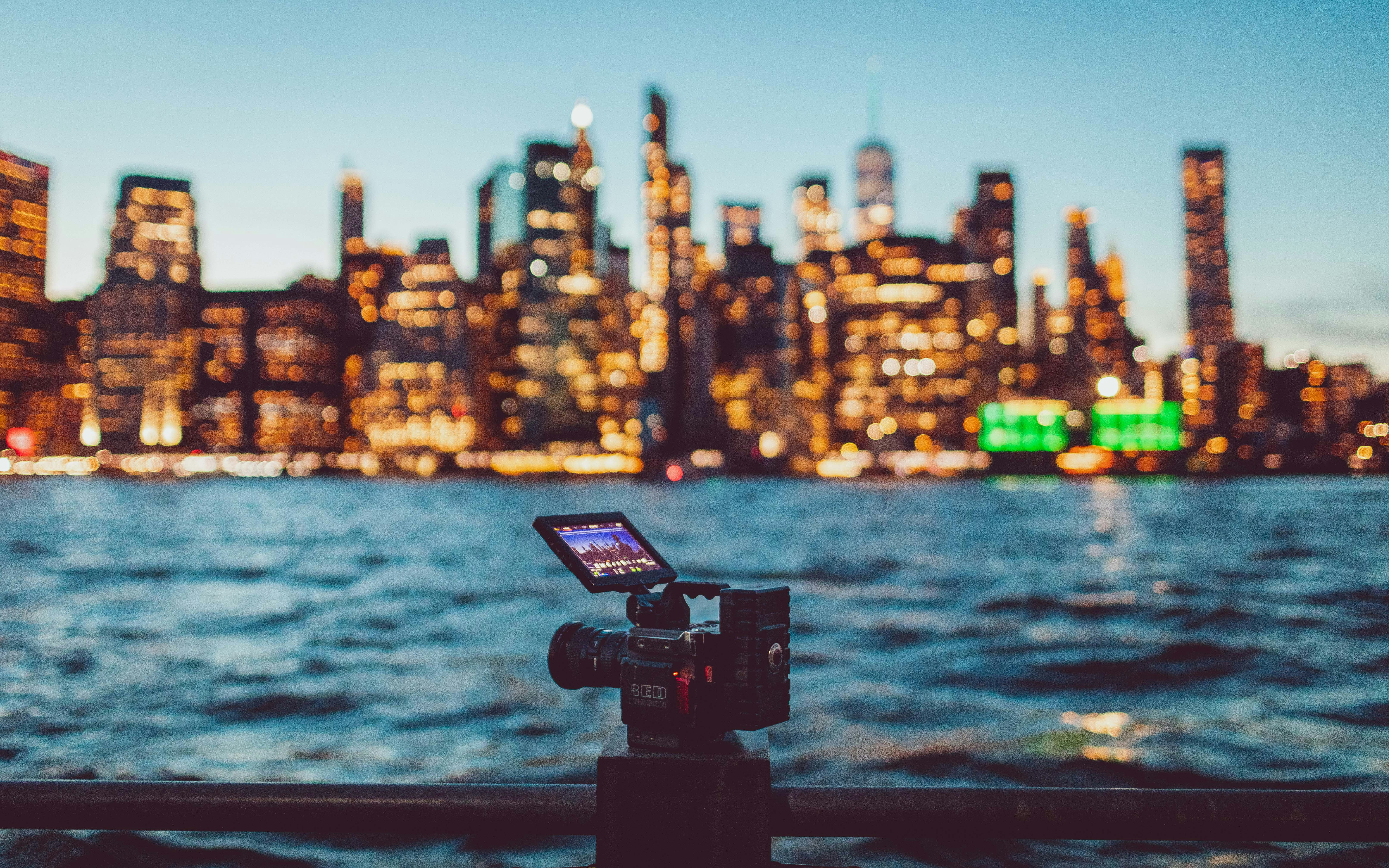 Camera set against a blurred city skyline during twilight.