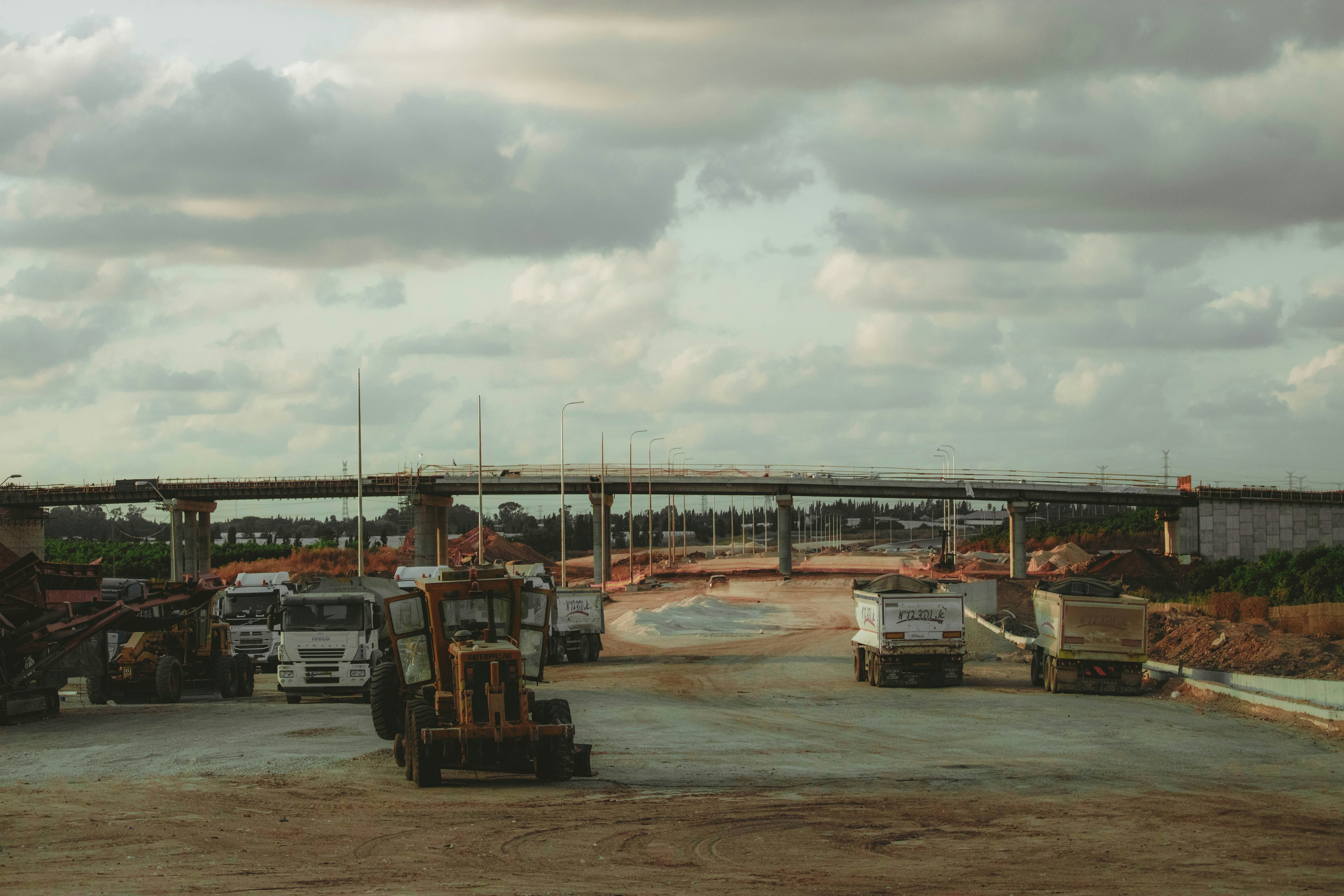 A construction site with trucks and a bridge in the background photo ...