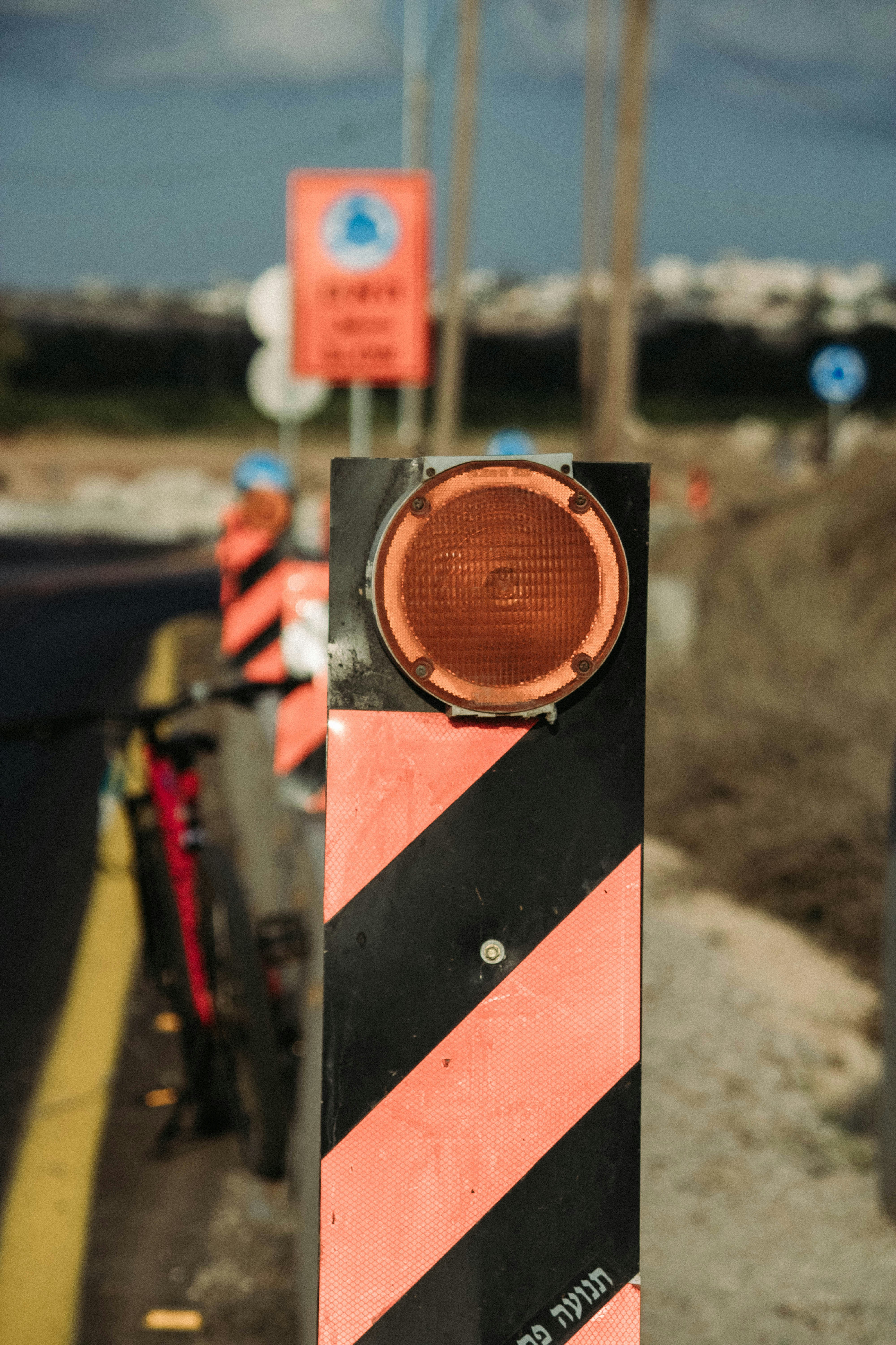 Copper beacon on a striped barrier at a roadside construction site