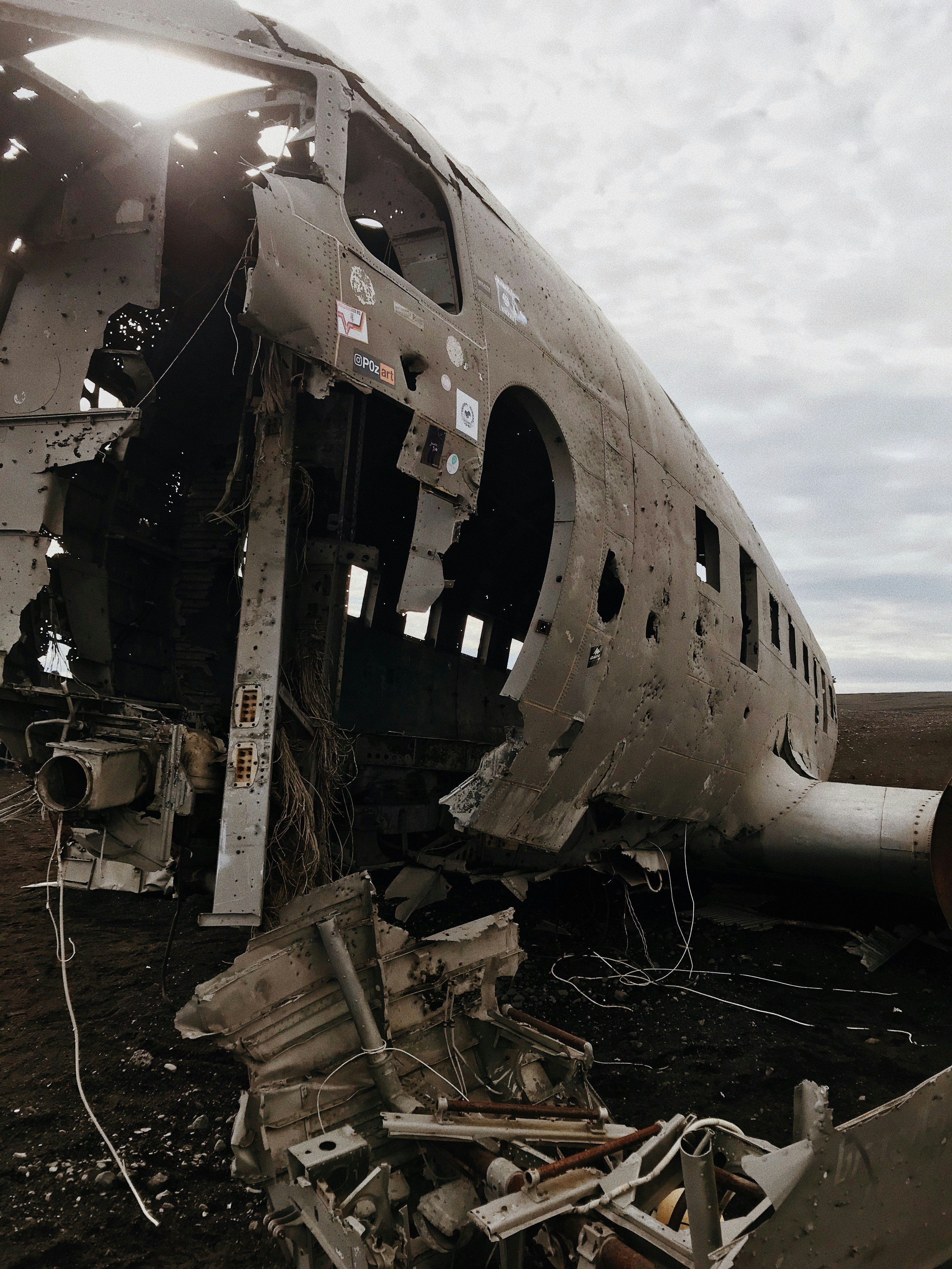 A weathered airplane wreckage reveals its interior, showcasing rusted metal and remnants of machinery amidst a desolate landscape.