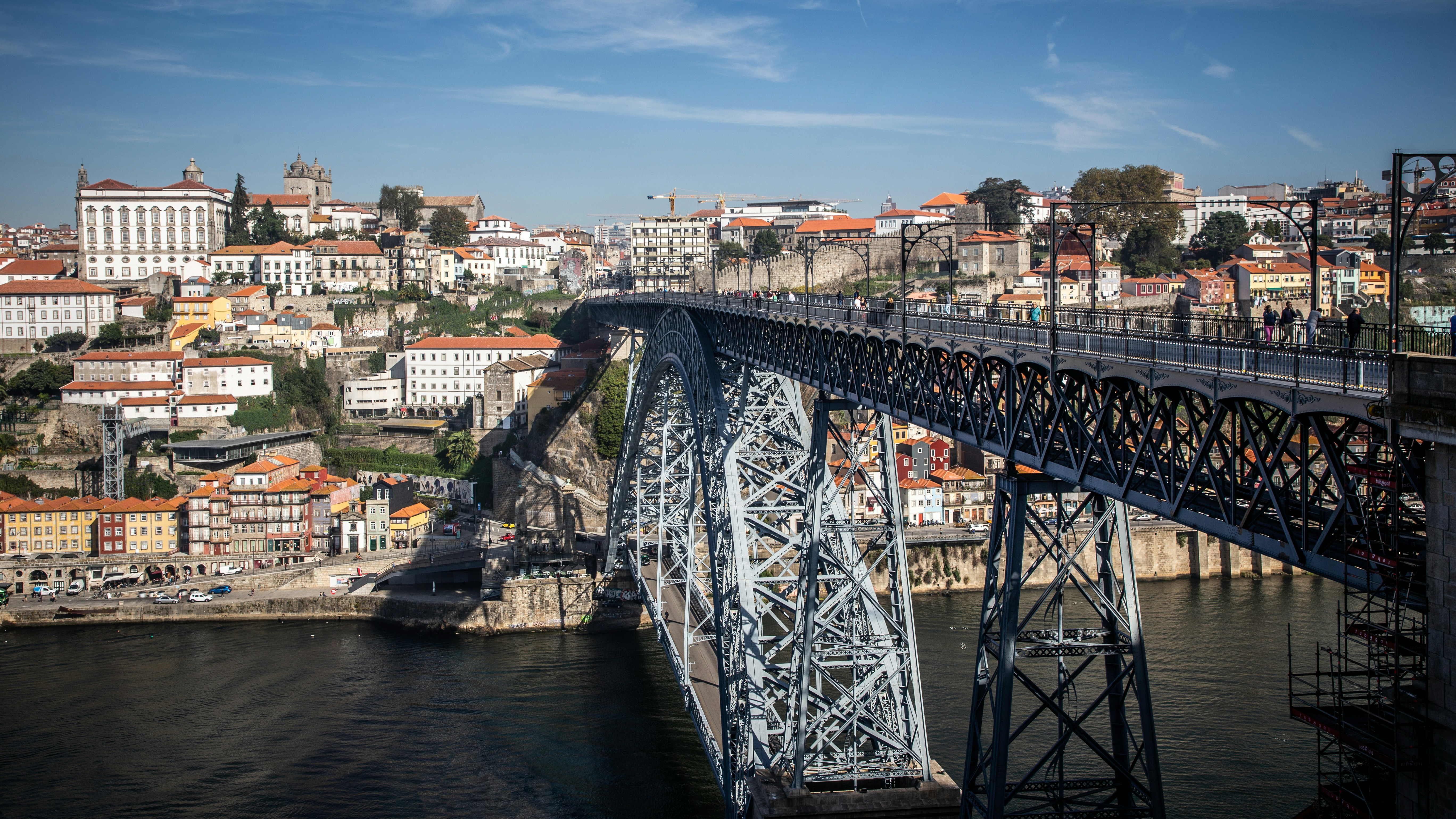 Iconic iron bridge spanning the Douro River, with Porto's colorful hillside buildings in the background. A vibrant scene capturing the essence of urban life.