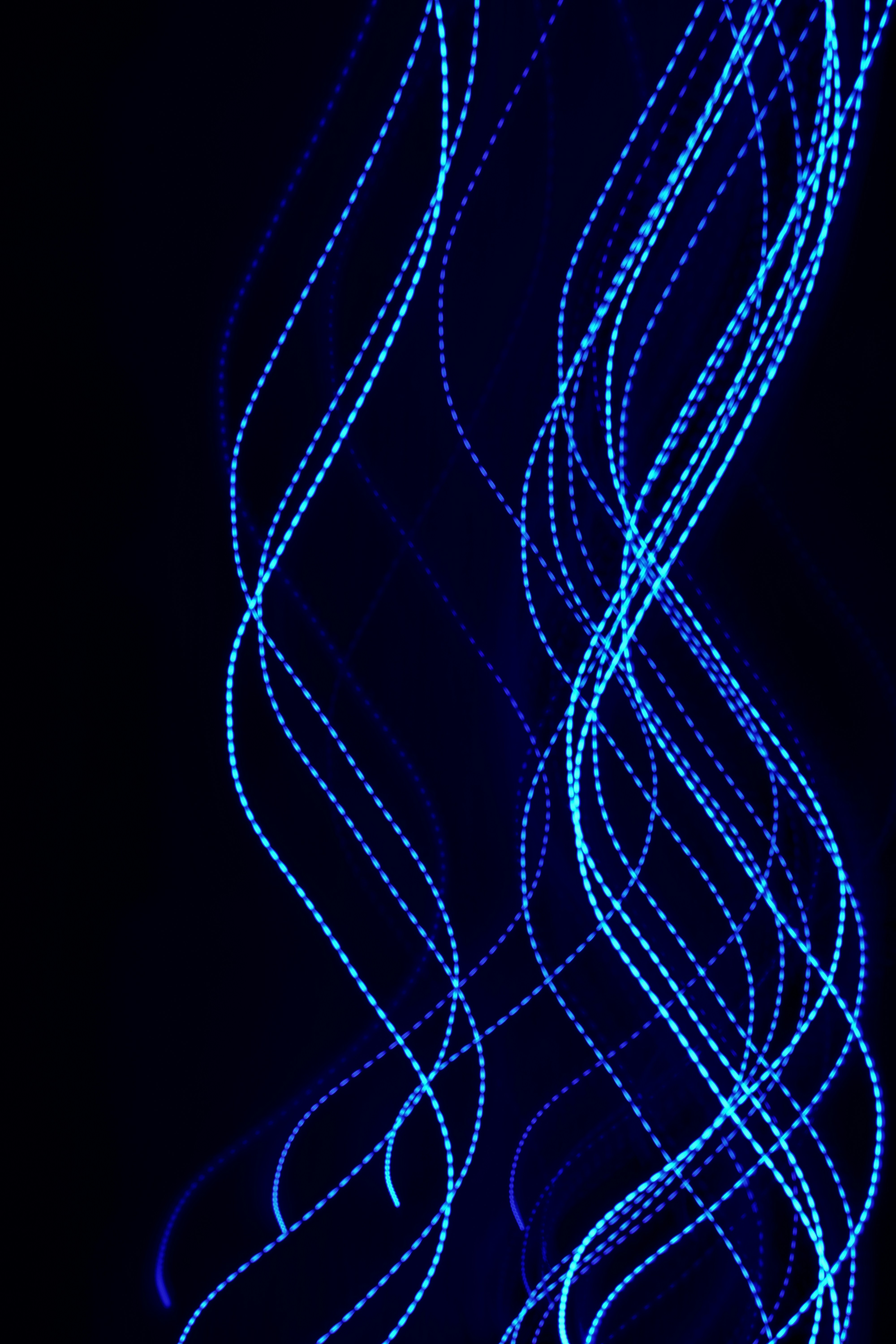 Abstract light trails in vibrant blue against a dark backdrop, showcasing the fluidity and movement of light. 