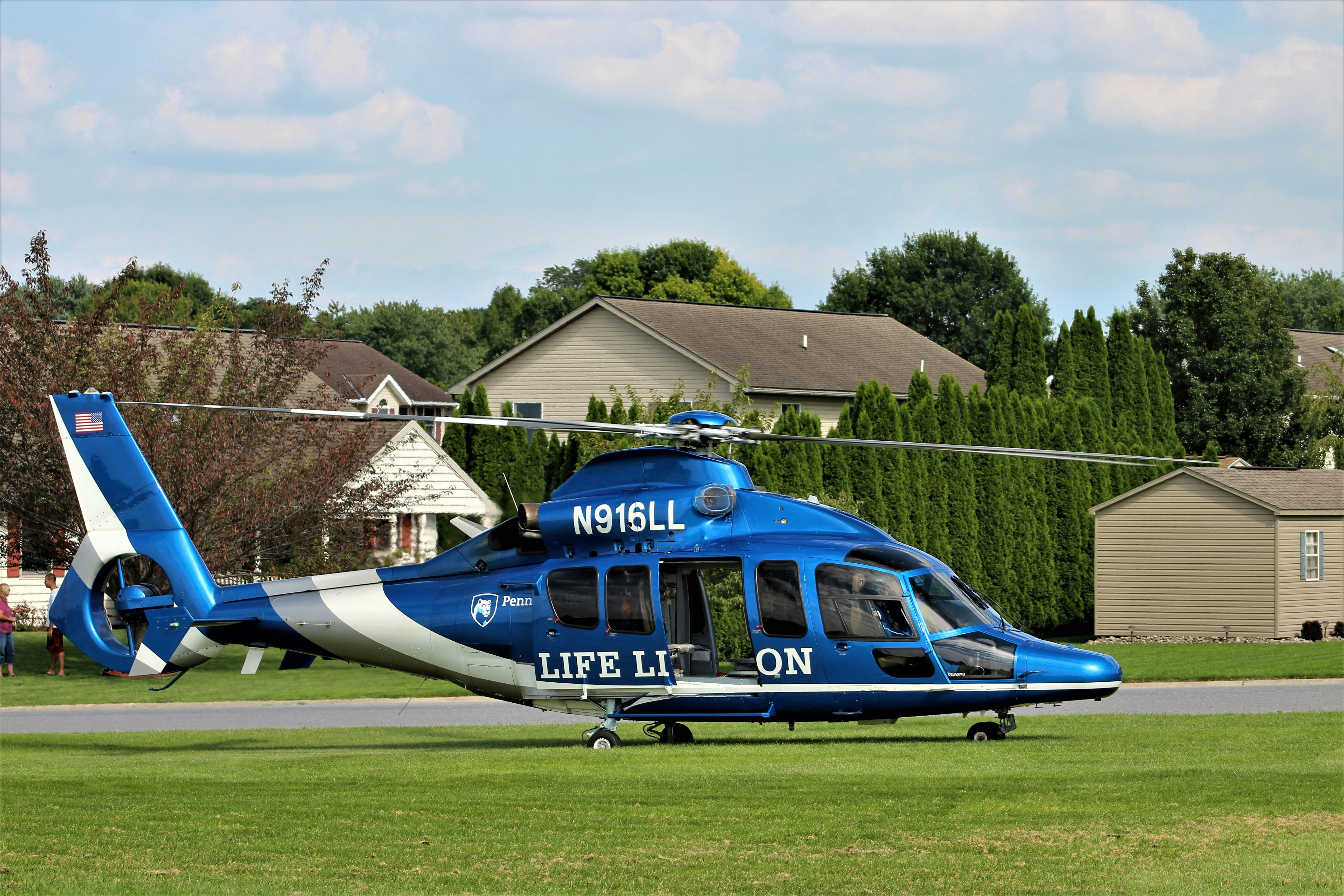 A blue and white helicopter sitting on top of a lush green field photo ...