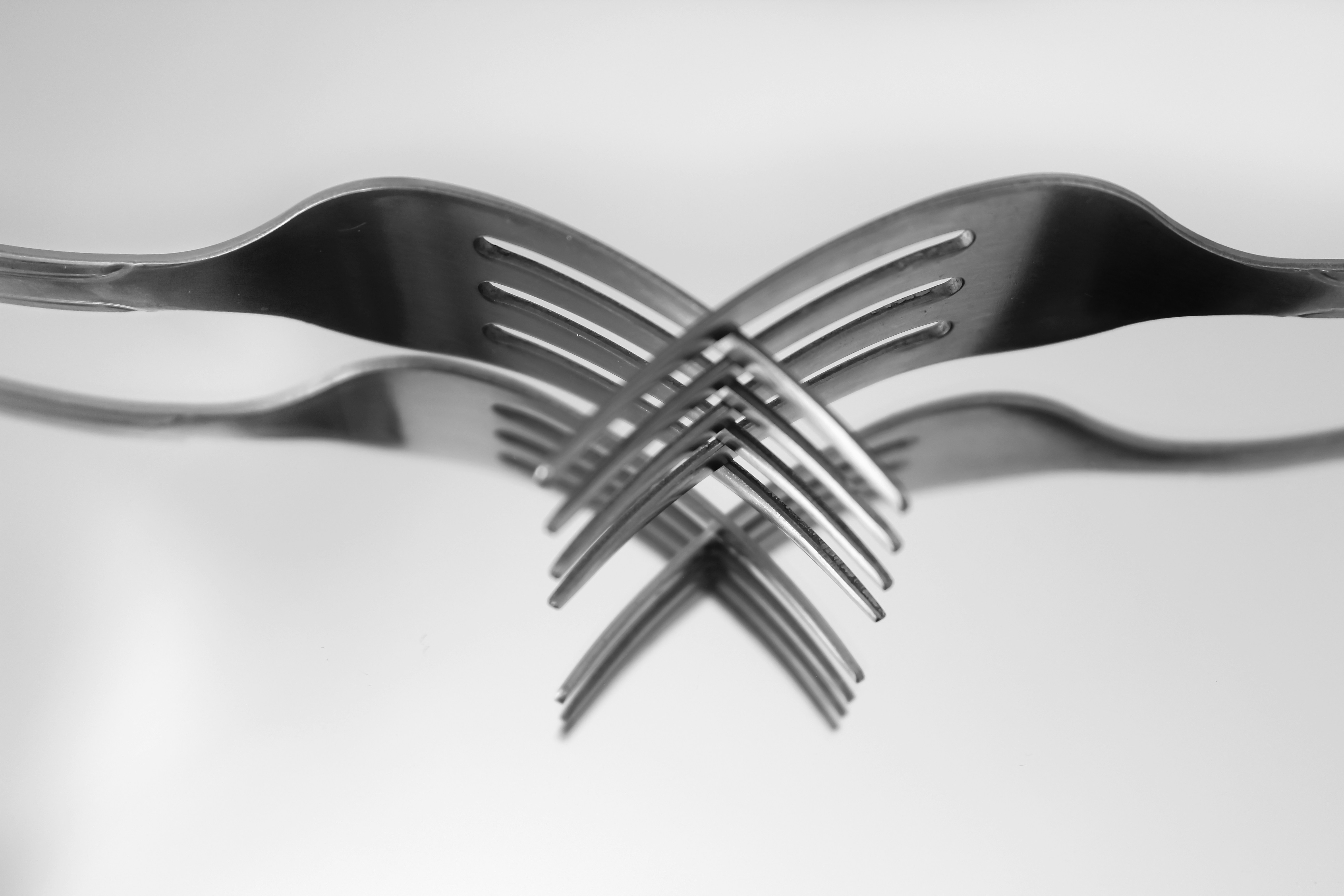 A creative arrangement of forks intersecting in a symmetrical pattern, showcasing their sleek design and metallic sheen.