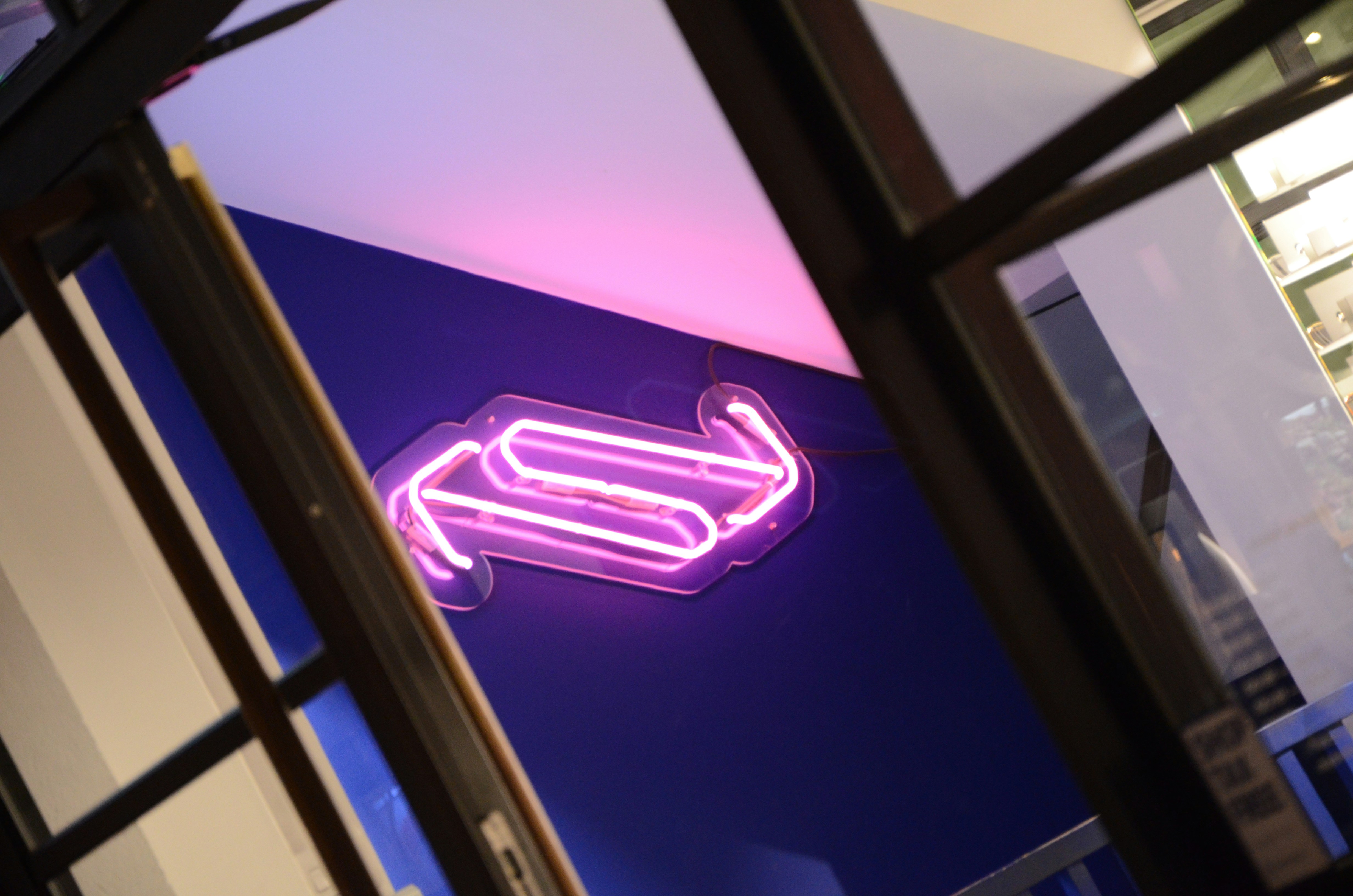 A neon sign hanging from the side of a building photo – Free Light ...