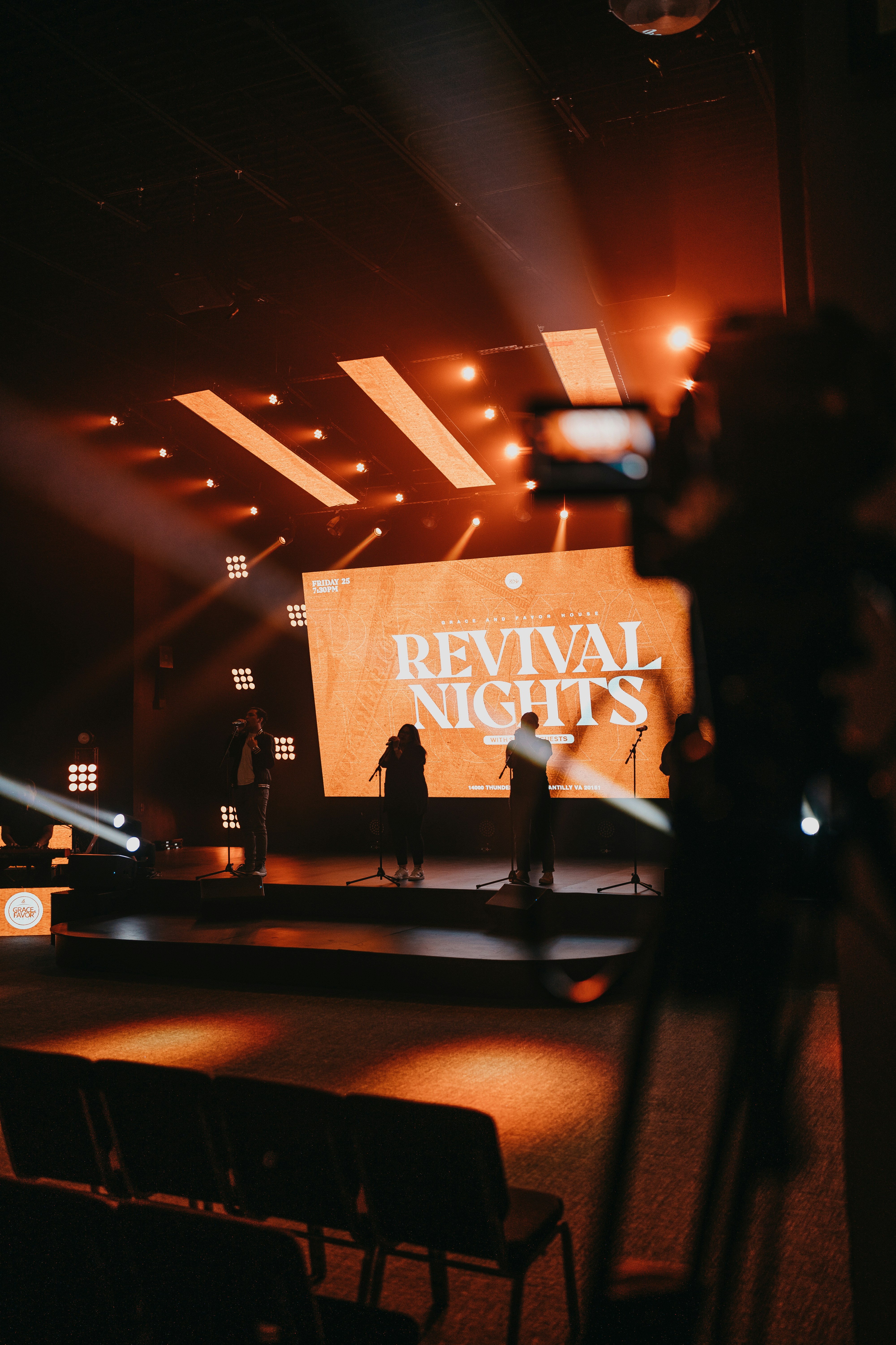 A stage with a projector and a screen with the words revival nights on ...