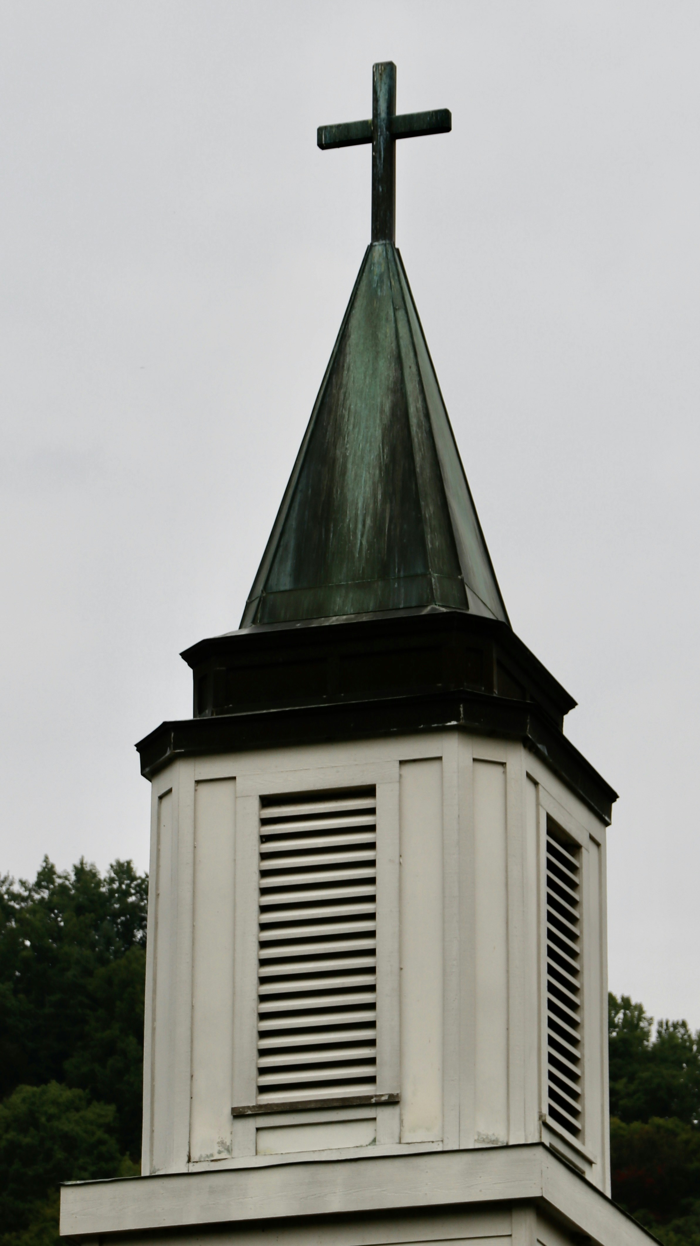 Copper-Capped Spire: Cross-Topped Church Tower Reaching Into a Pale Sky
