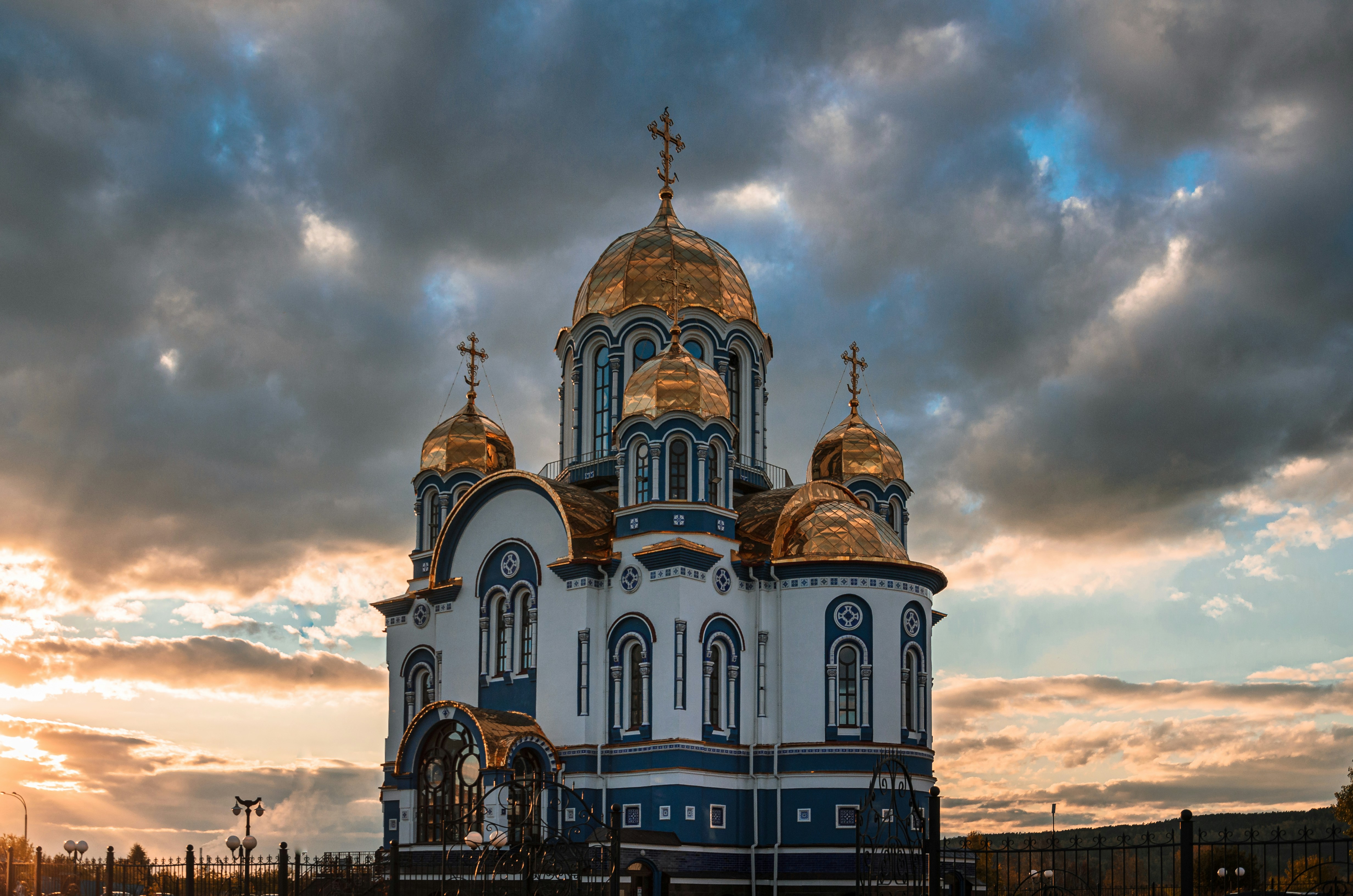 White and Brown Concrete Church Under Cloudy Sky | a large white and blue building with gold domes