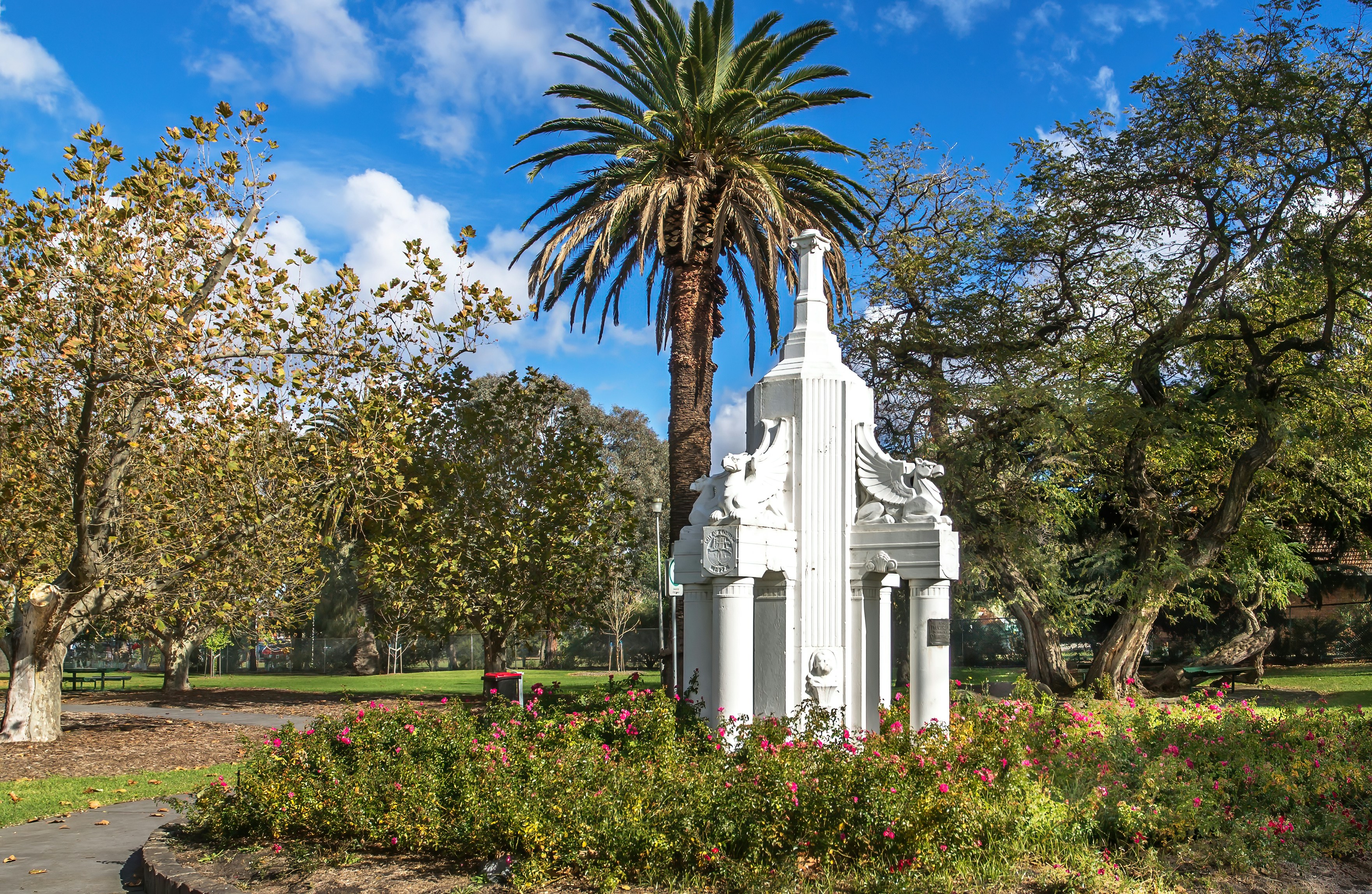 Sunlit Monolith Among Palm and Bloom in a City Park