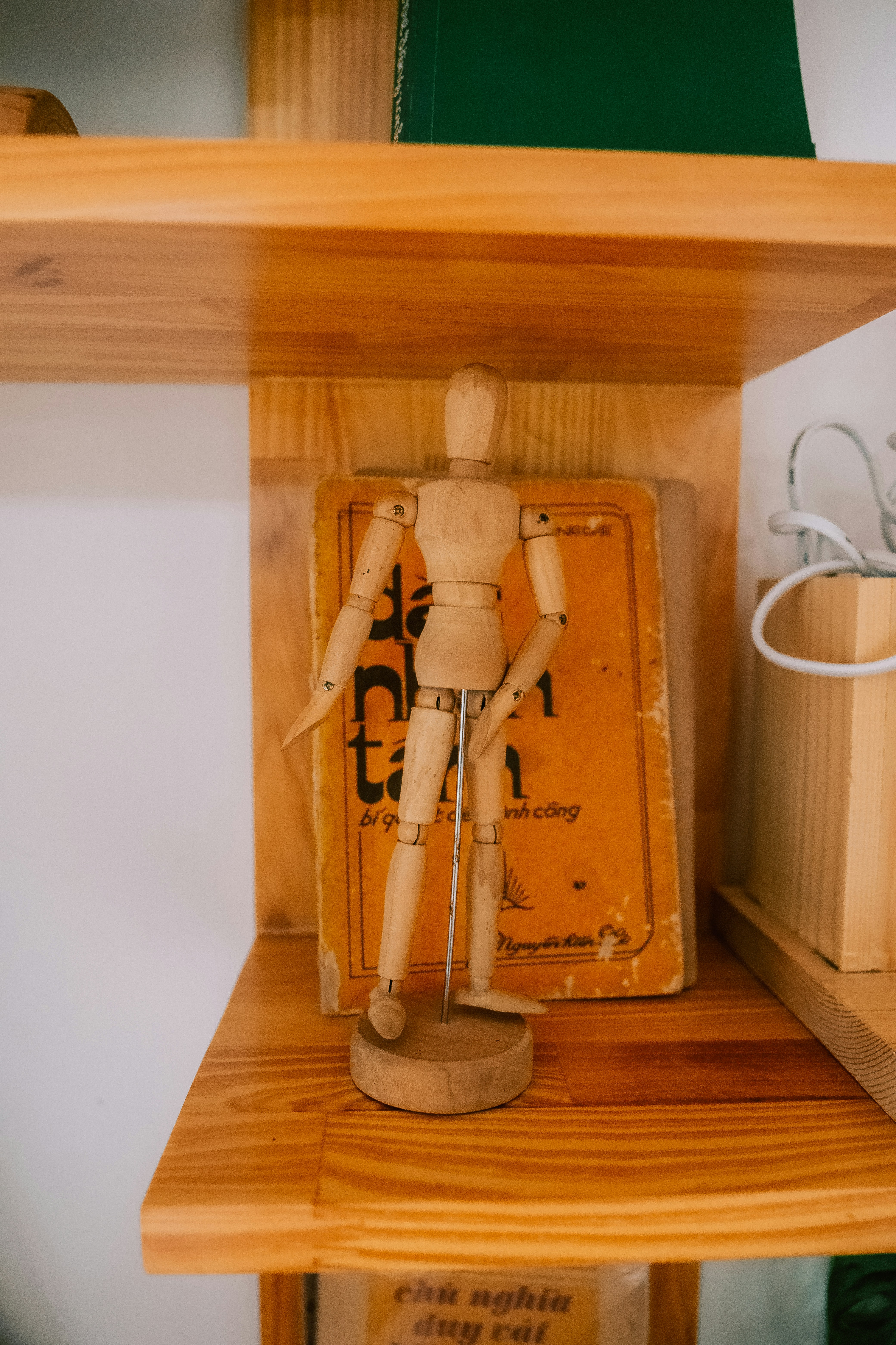 Shelfbound Studio Figure: Wooden Artist in Warm Backlit Nest with a Vintage Orange Book