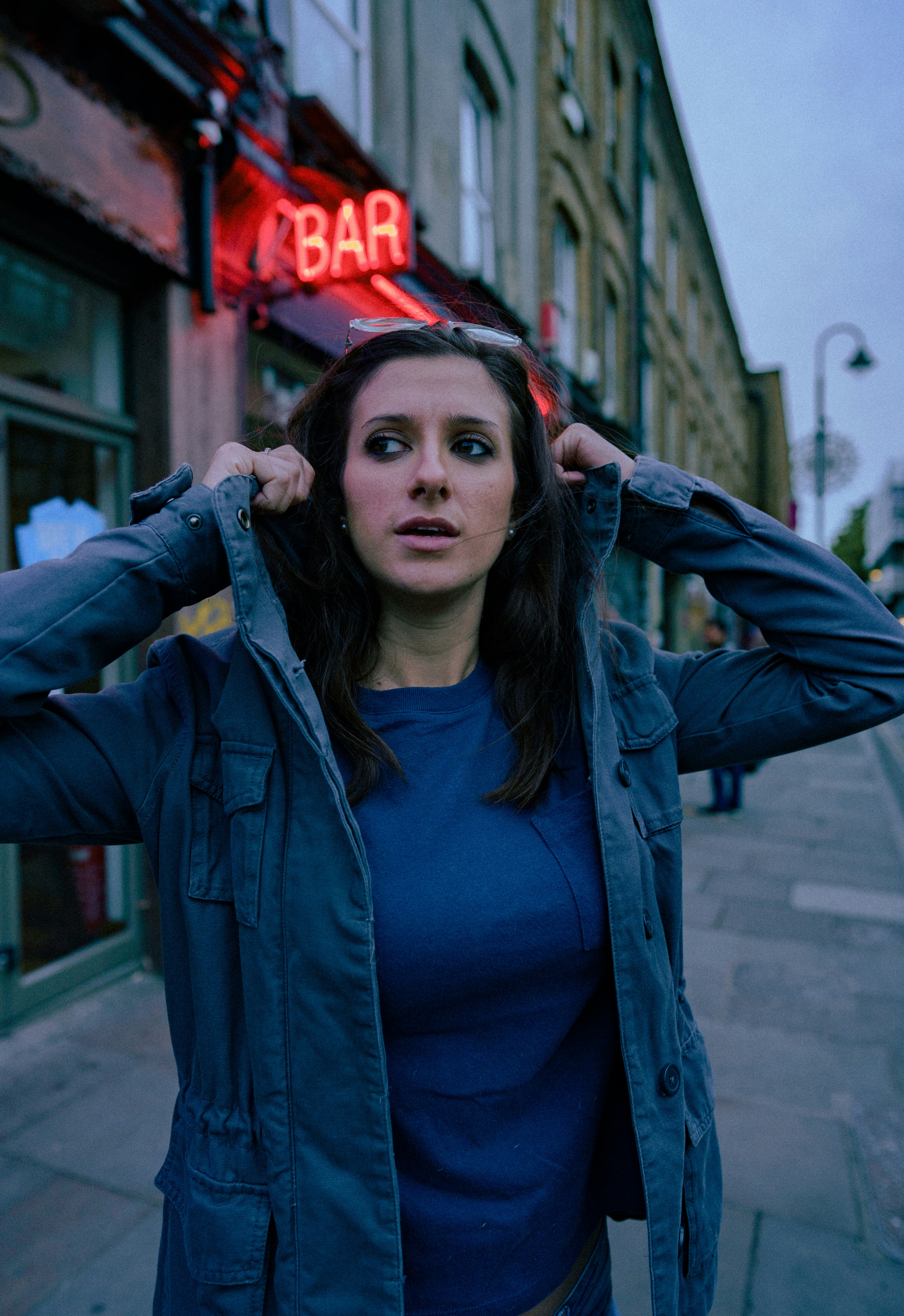 Neon Bar Gaze: Street Portrait Beneath Blue Neon