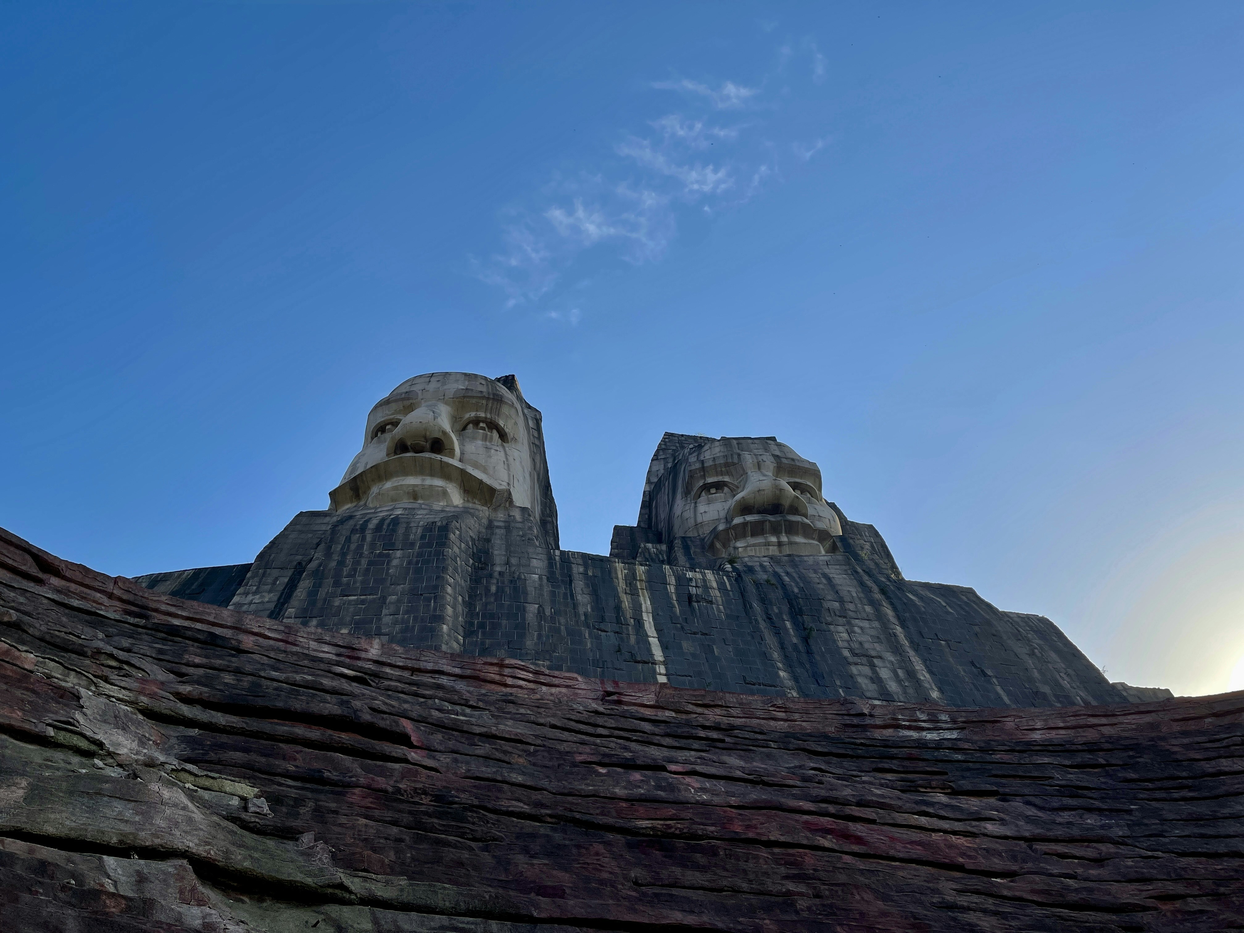 Two large statues of heads on top of a mountain photo – Free China ...
