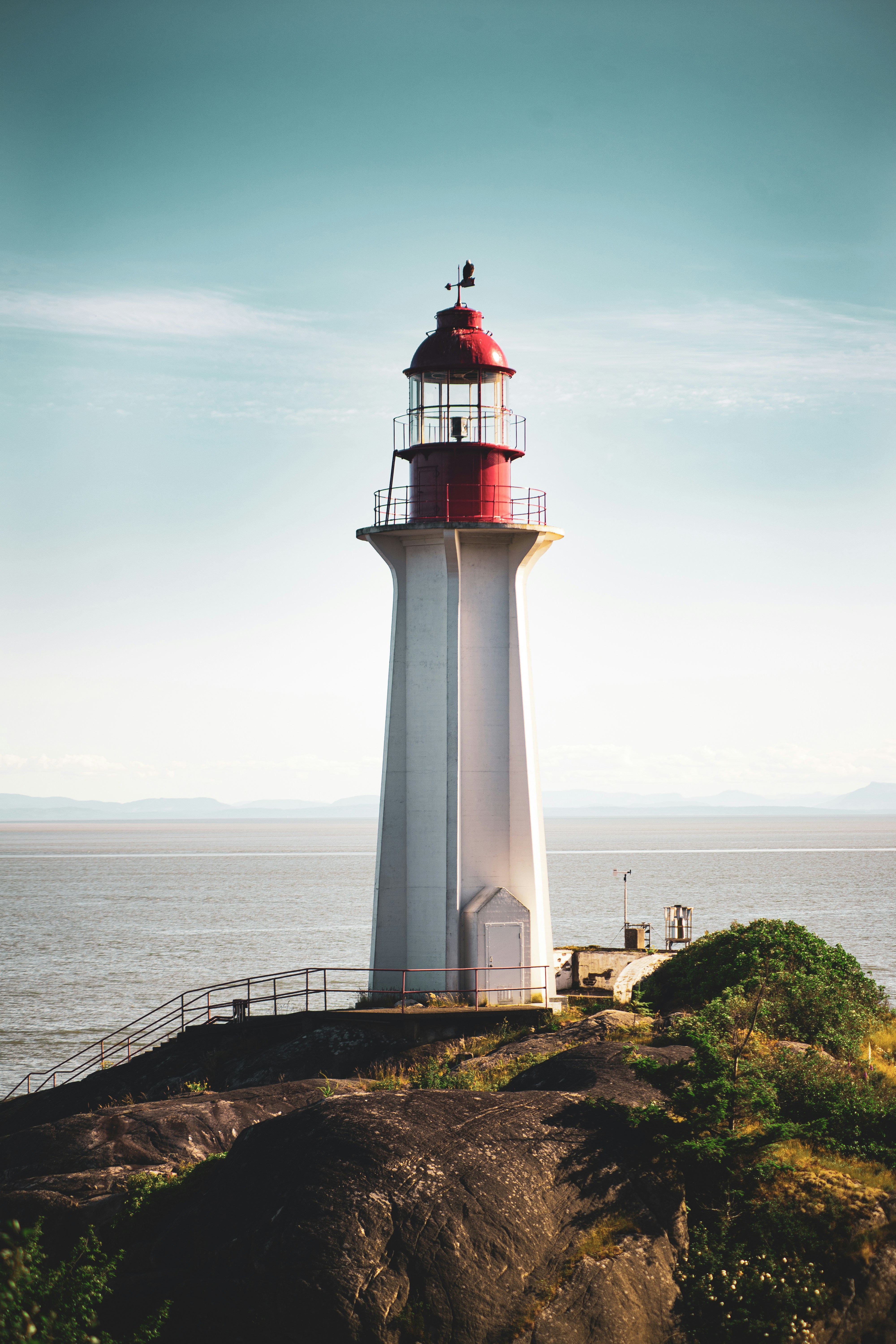 a white and red lighthouse sitting on top of a cliff