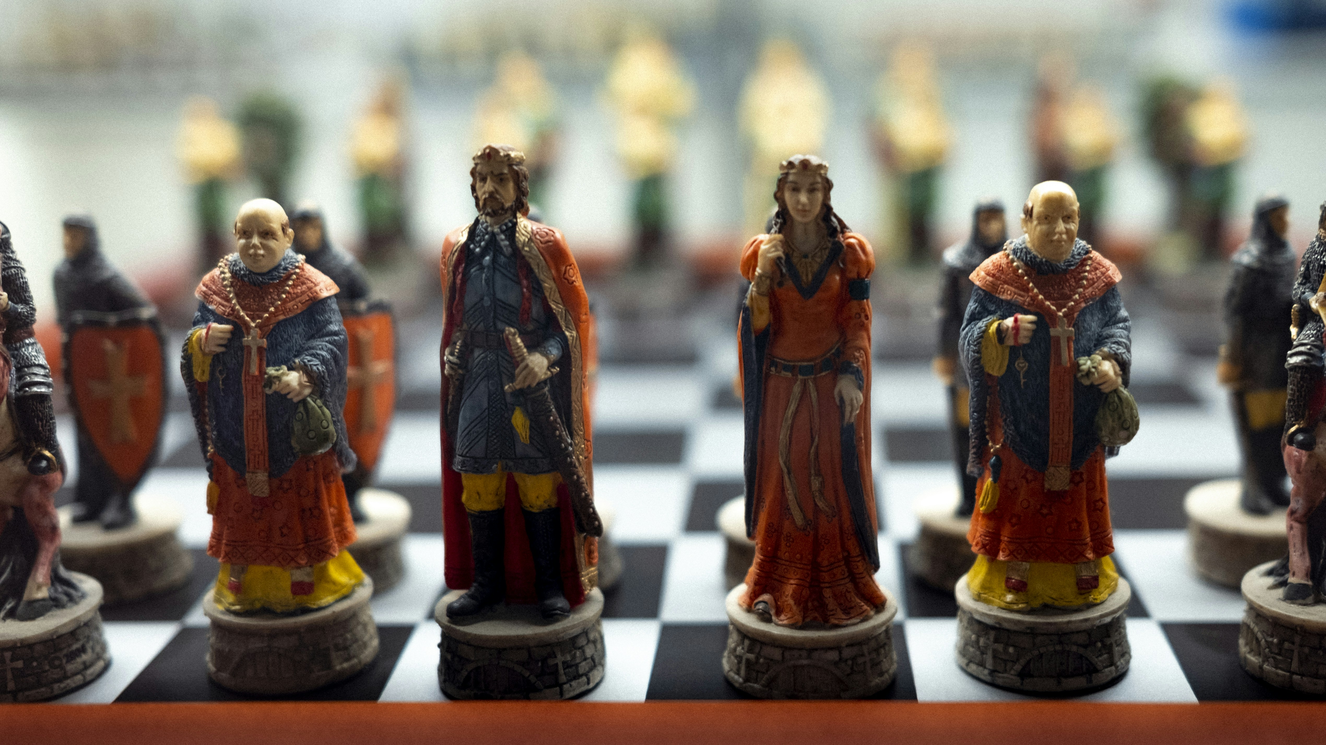 Intricately designed chess pieces arranged on a board, showcasing a medieval theme with regal characters. The scene captures the essence of strategic gameplay.