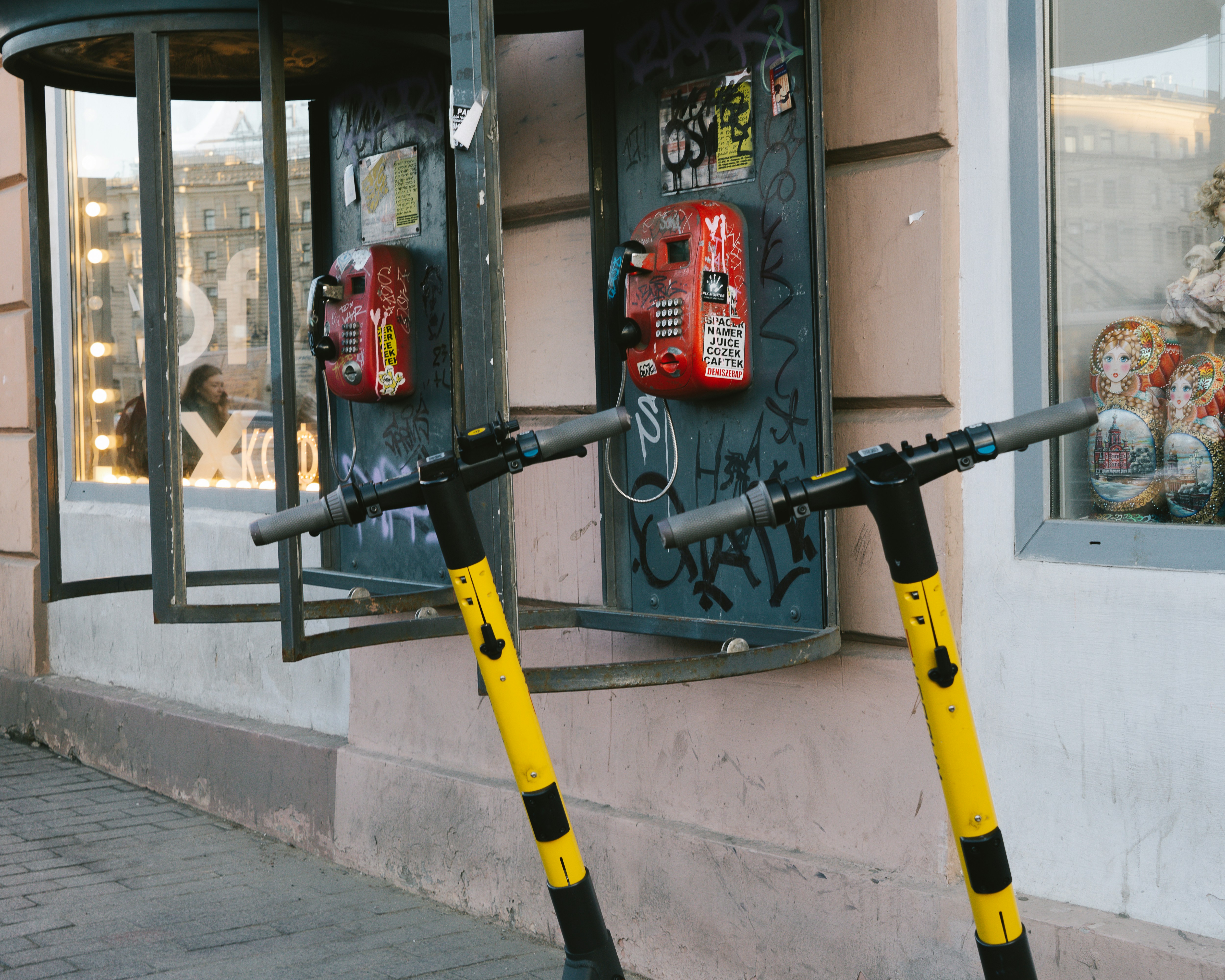 Two Yellow Kick Scooters Stand as Sentinels Before a Graffiti-Dusted Storefront