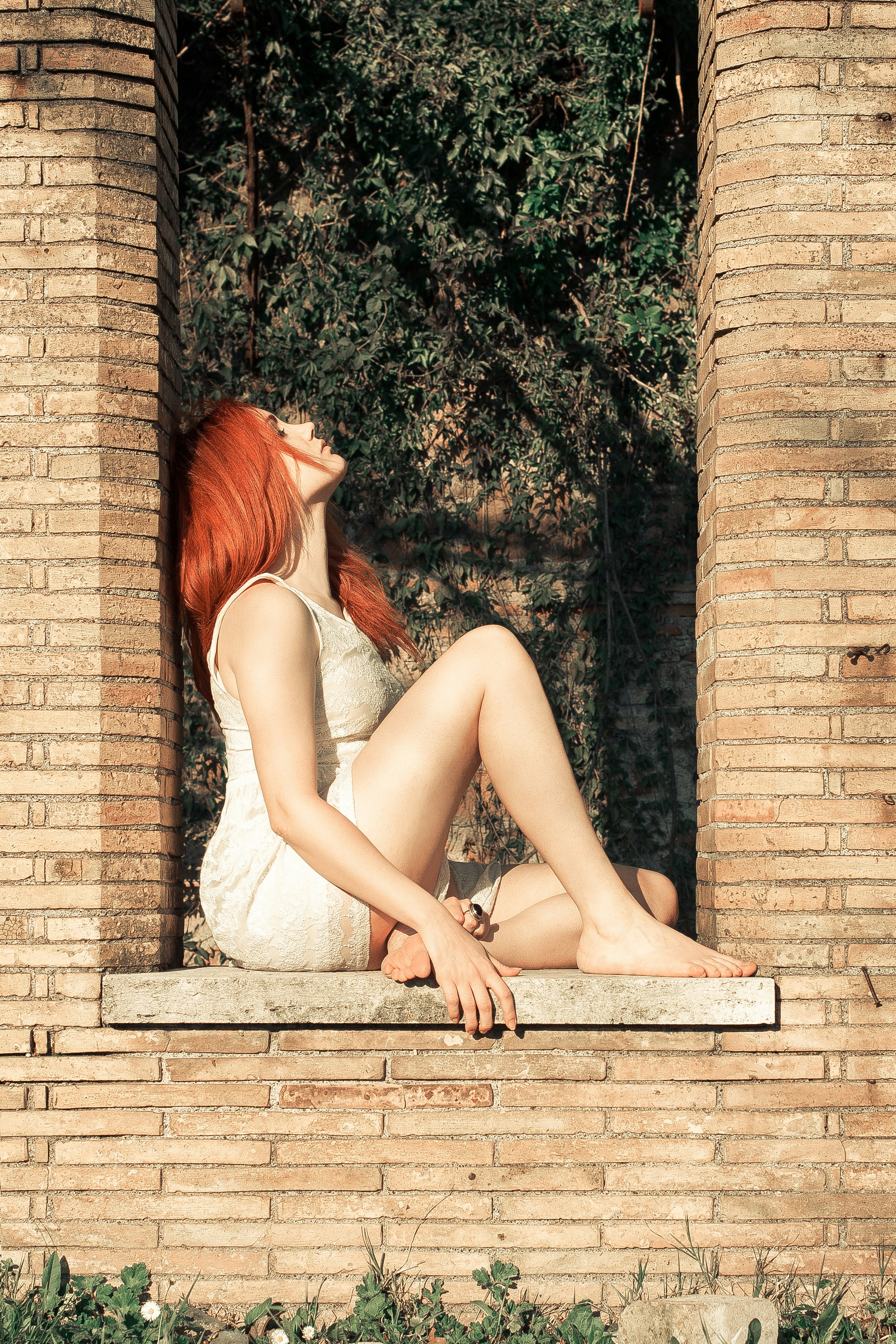 Sunlit Bricks, Red Hair: A White-Dress Moment in a Quiet Archway