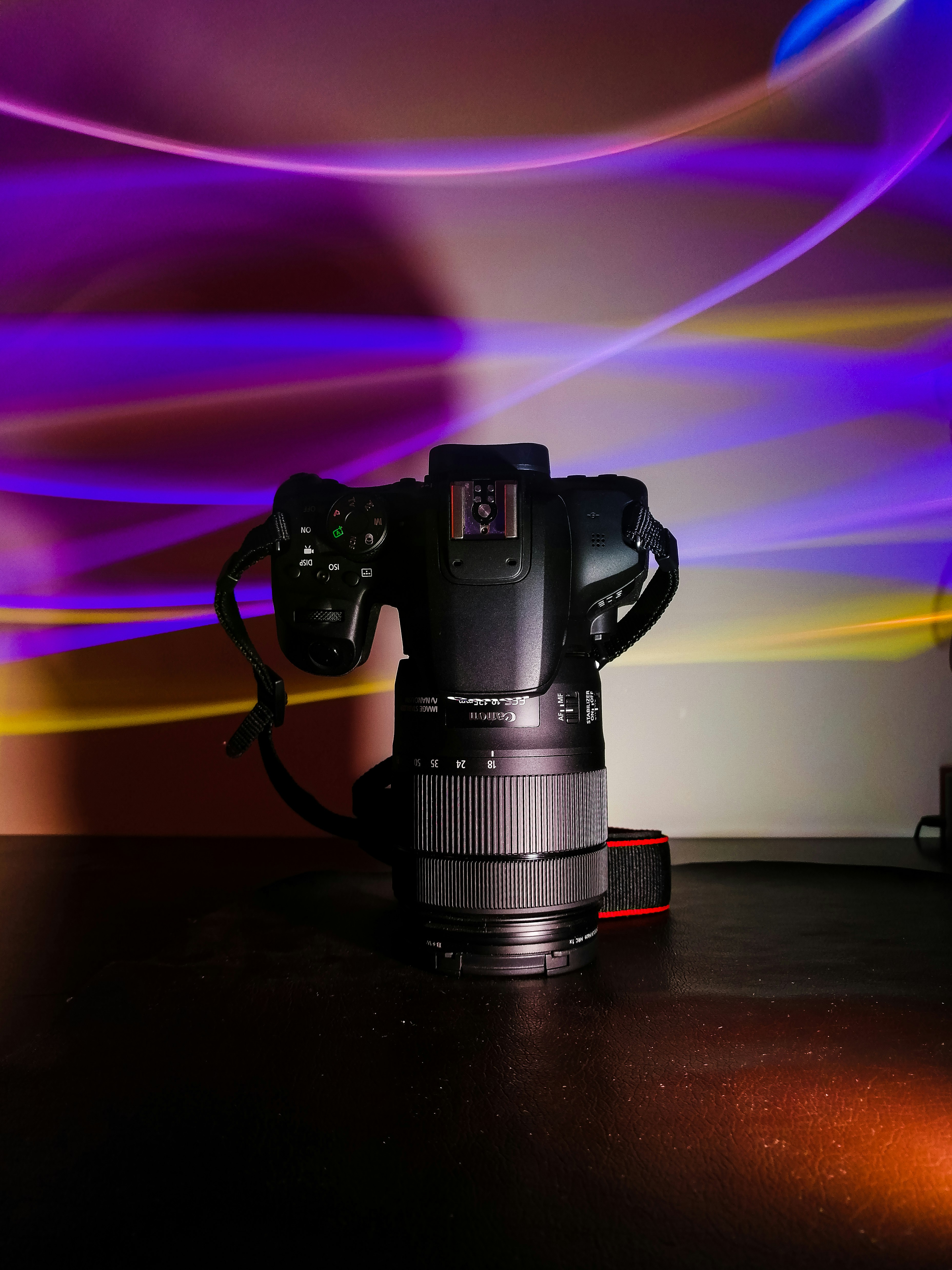 A camera stands prominently against a backdrop of colorful light trails, showcasing the intersection of technology and artistry.