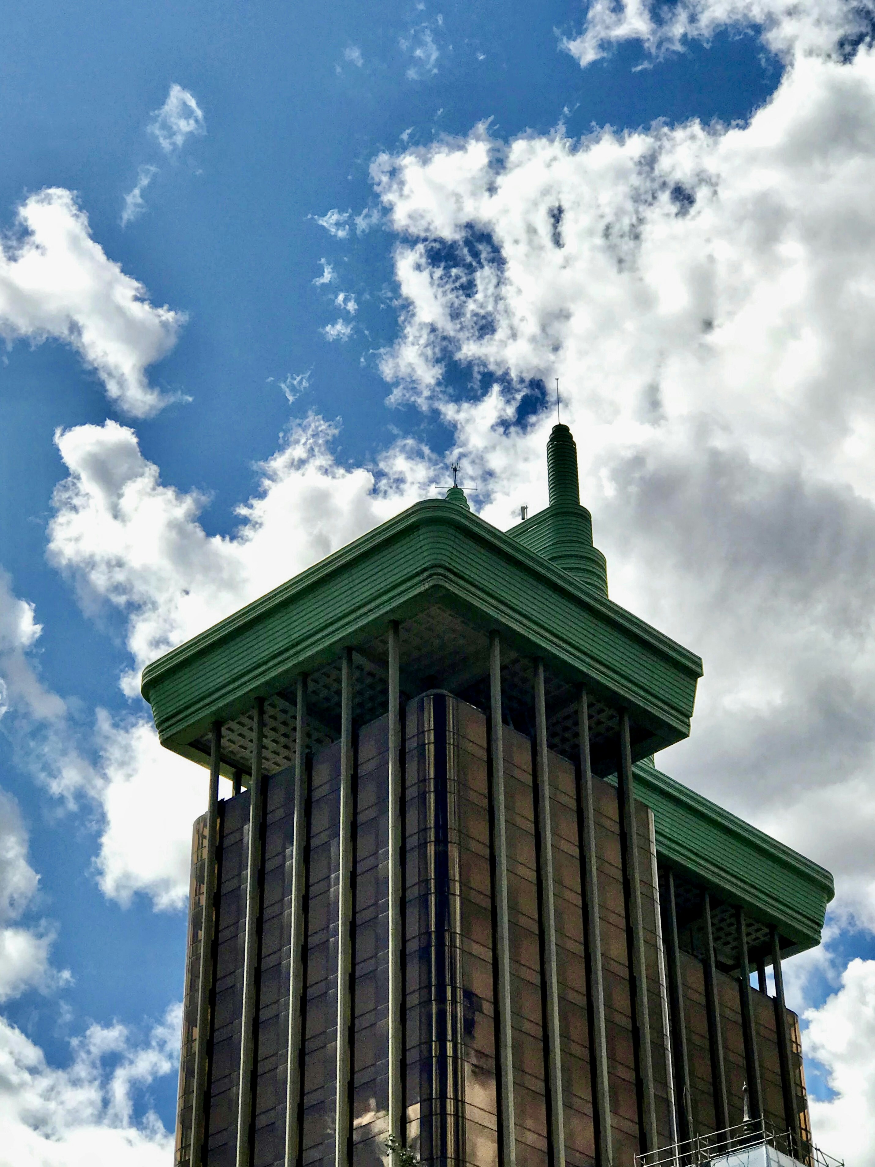 Verdant Crown Rising: A Green-Roofed Tower Against a Sky of Clouds