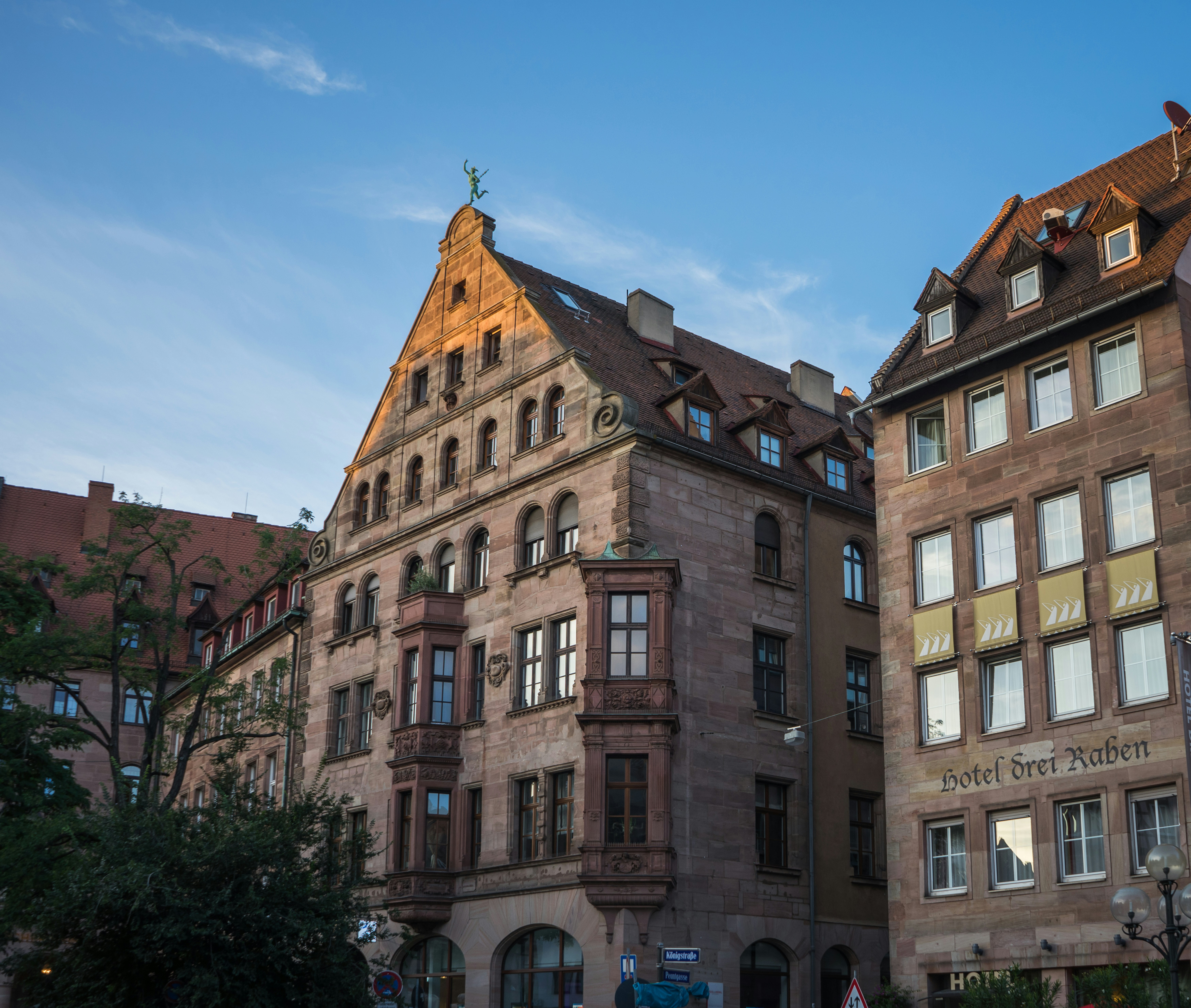 Historic buildings with steep gabled roofs bathed in warm evening light under a clear sky.