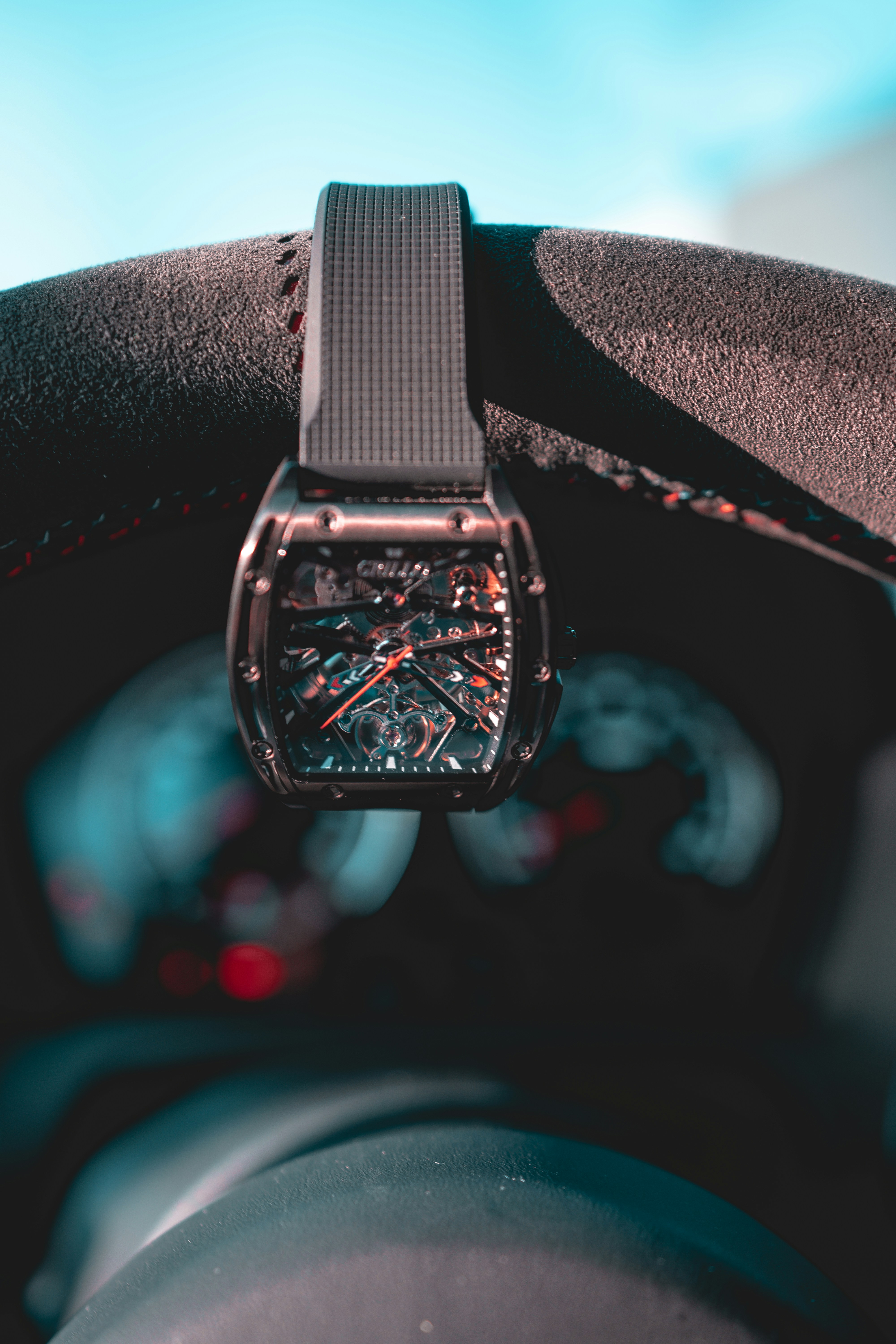 Stylish watch resting on a car steering wheel, showcasing intricate details against a blurred dashboard backdrop.