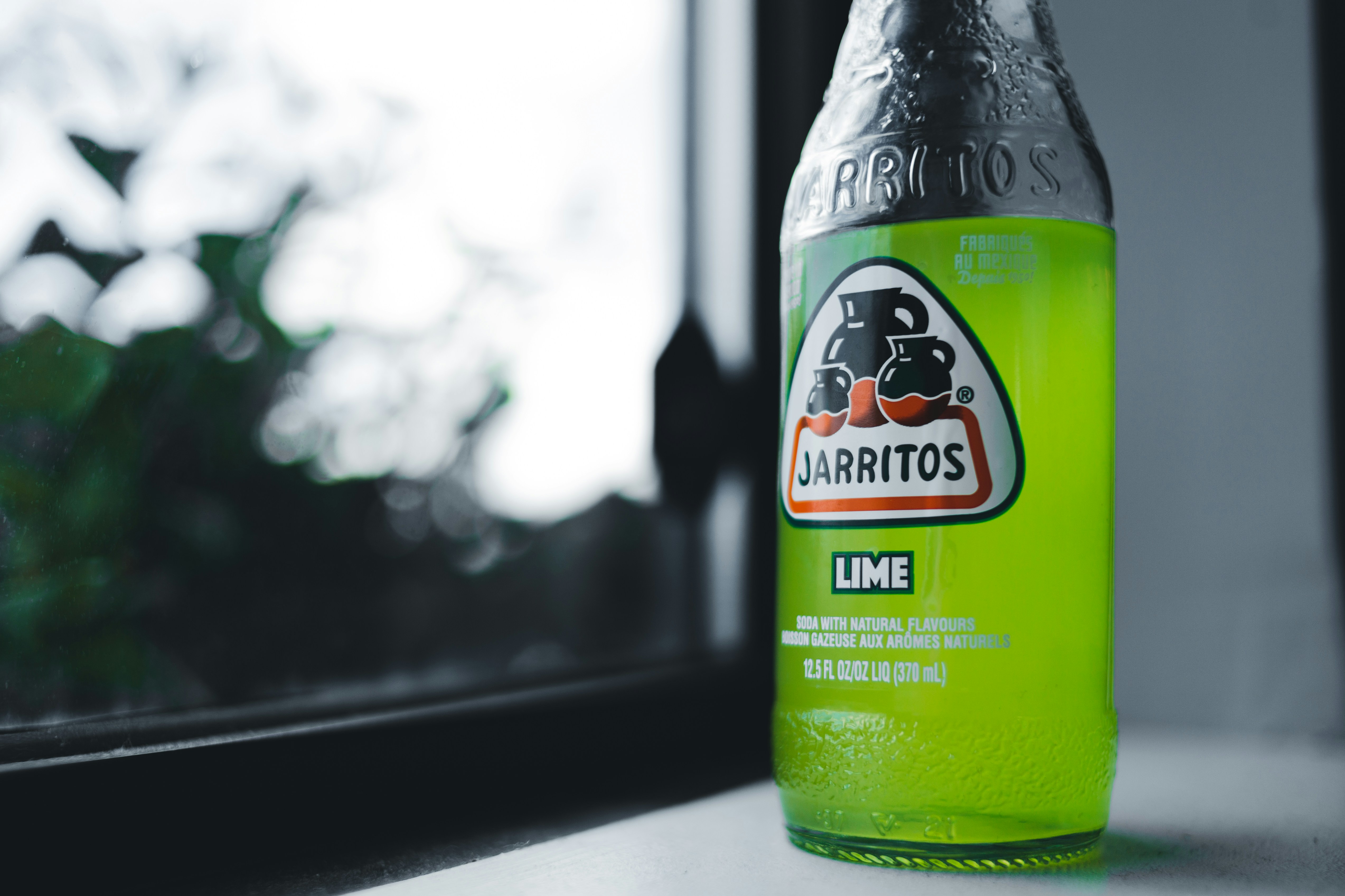 A bottle of lime soda sitting on a window sill photo – Free Green Image ...