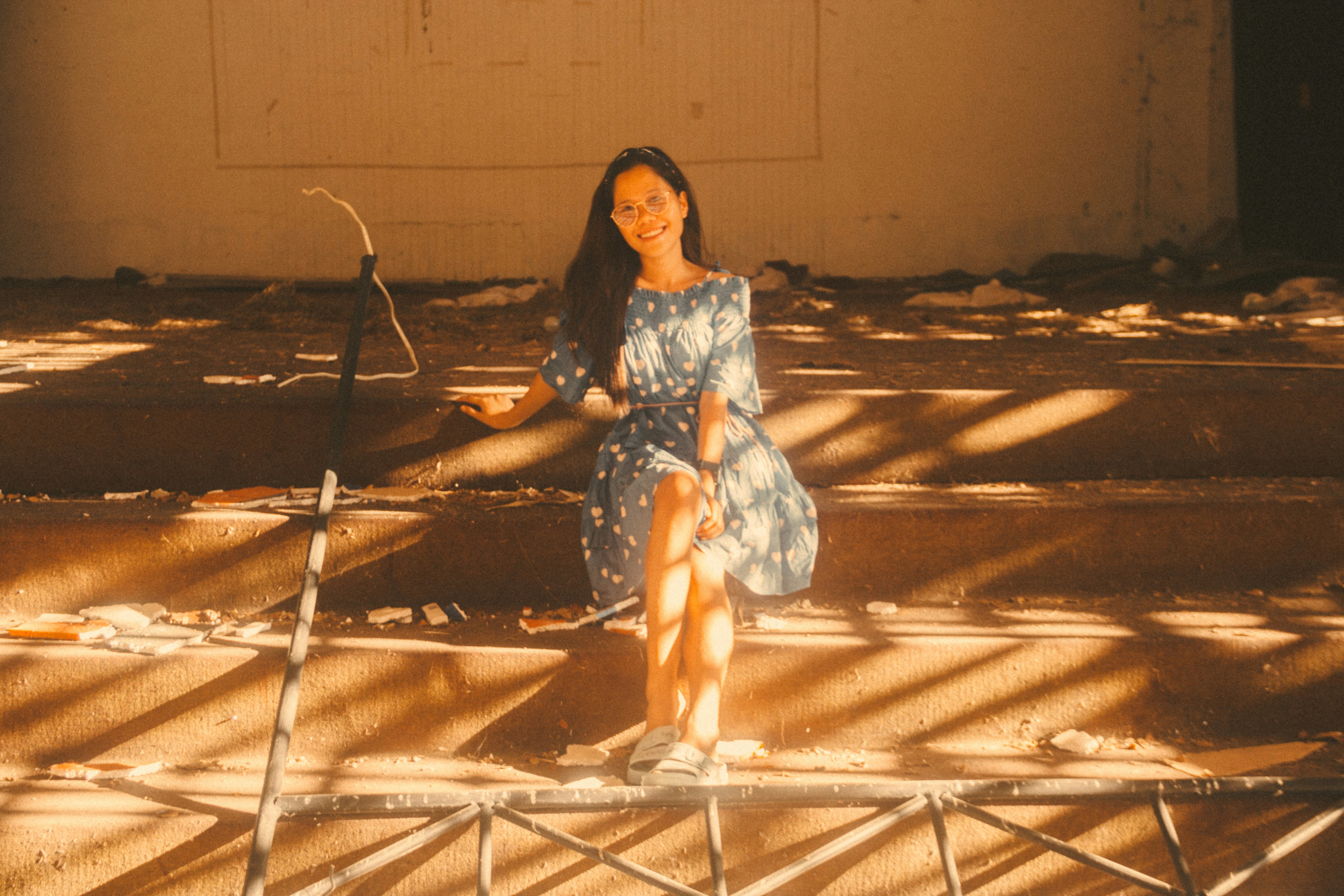 a woman in a blue dress sitting on a metal rail
