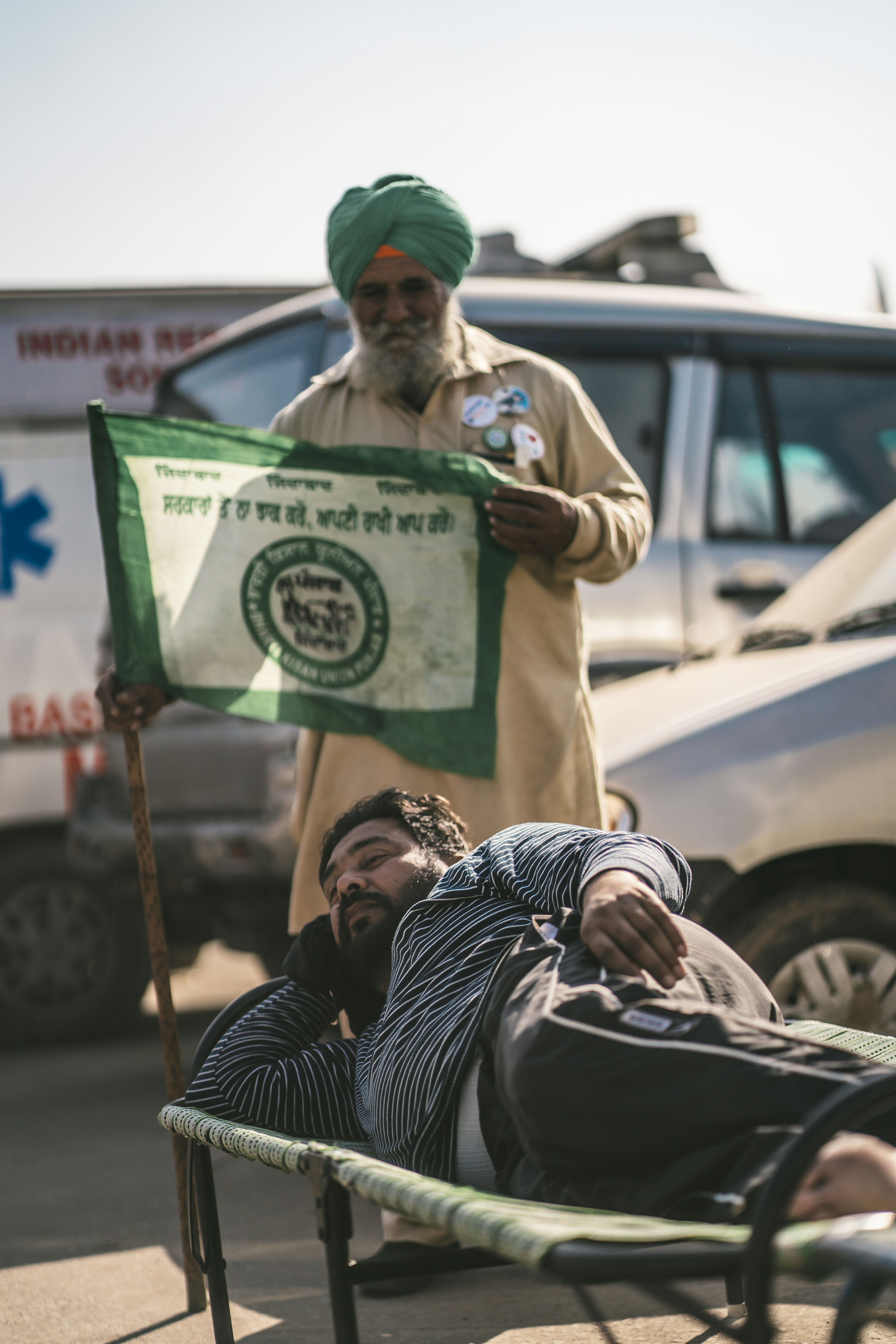 Flag bearer and a resting figure under a roadside vigil