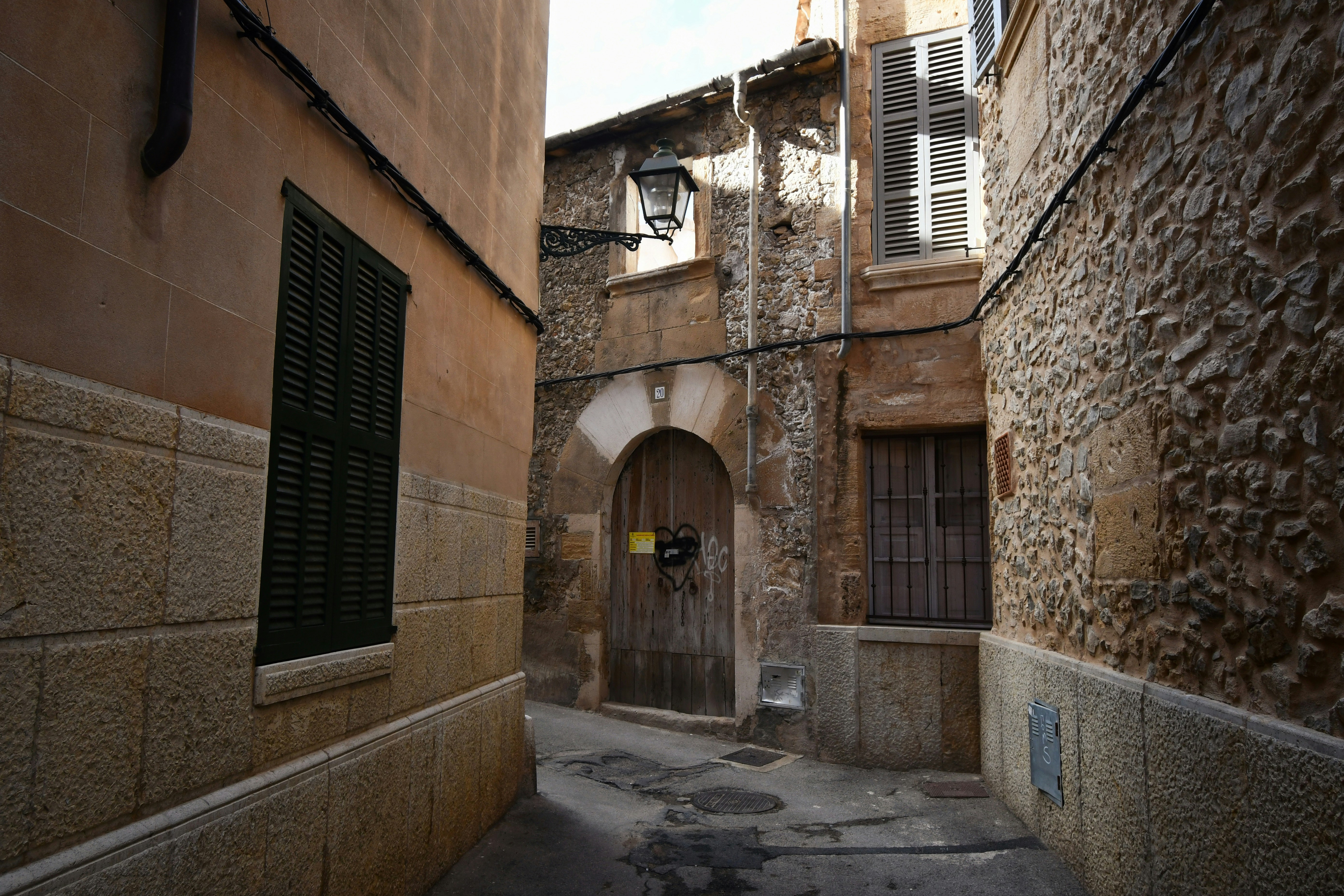 Narrow cobblestone street flanked by rustic stone buildings under soft daylight.