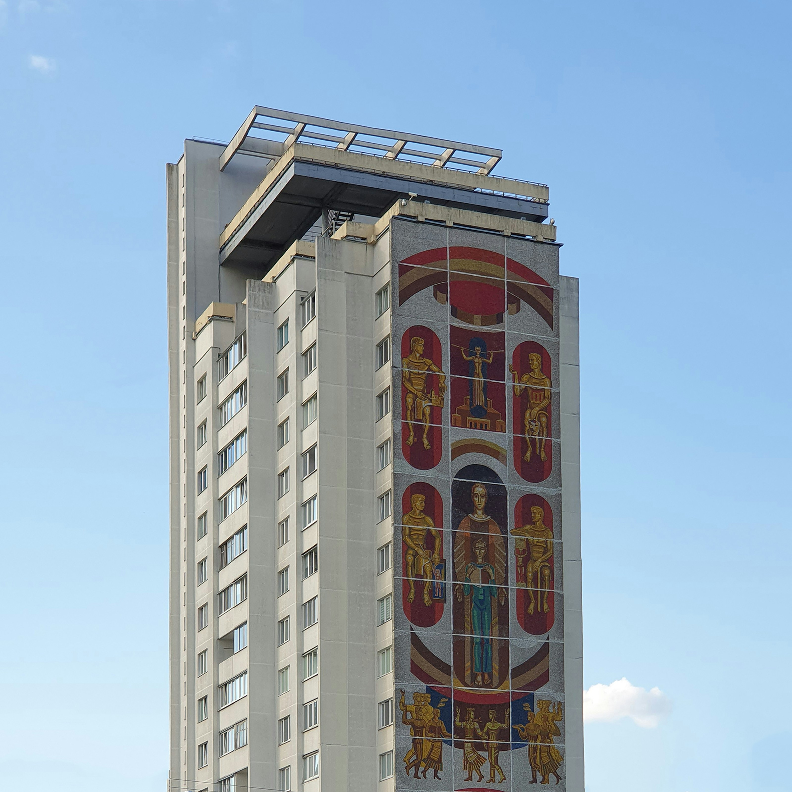 Vertical Shrine: A mural-adorned high-rise against a clear blue sky