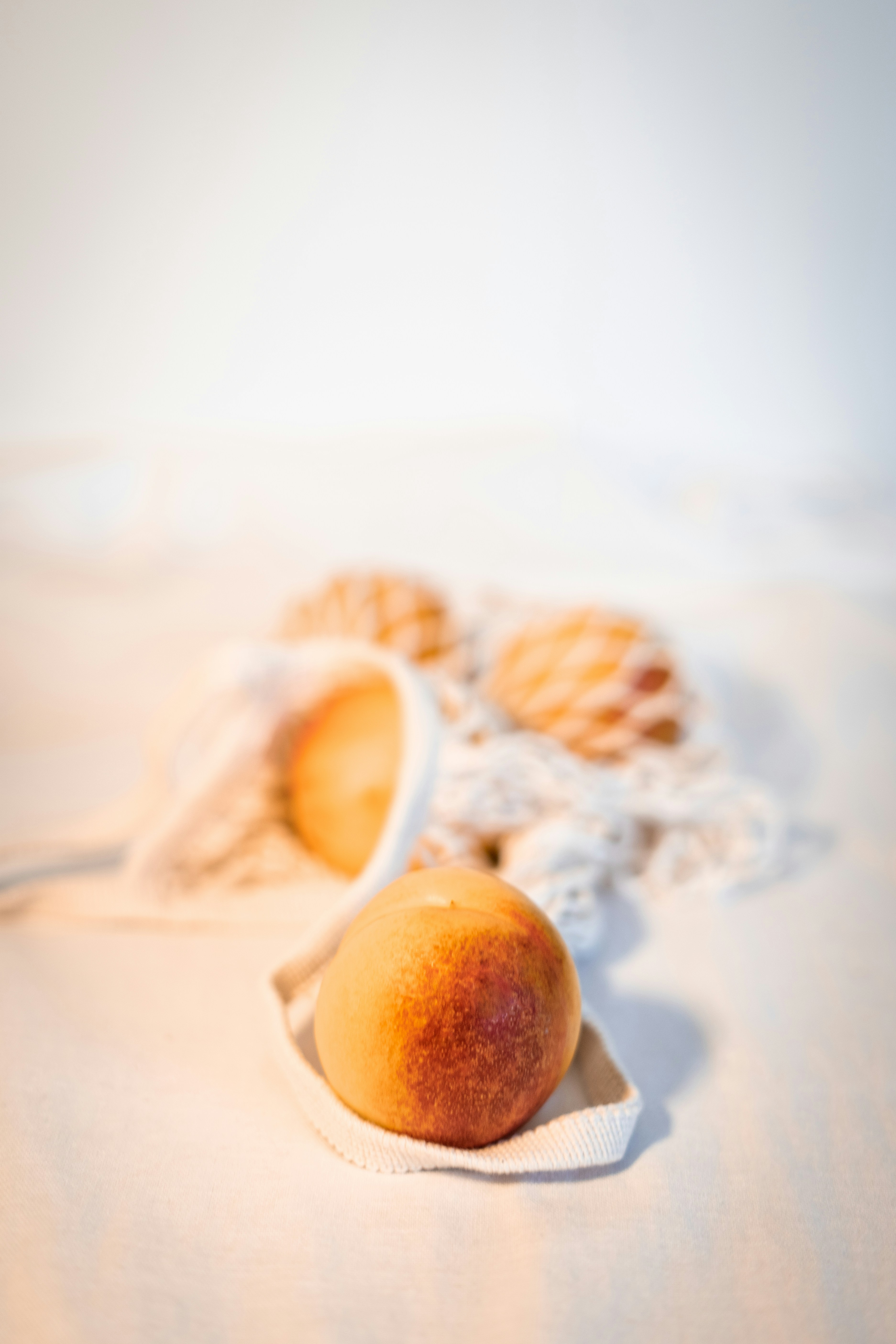 Peach in Soft Bloom: A Quiet Still-Life on White Linen