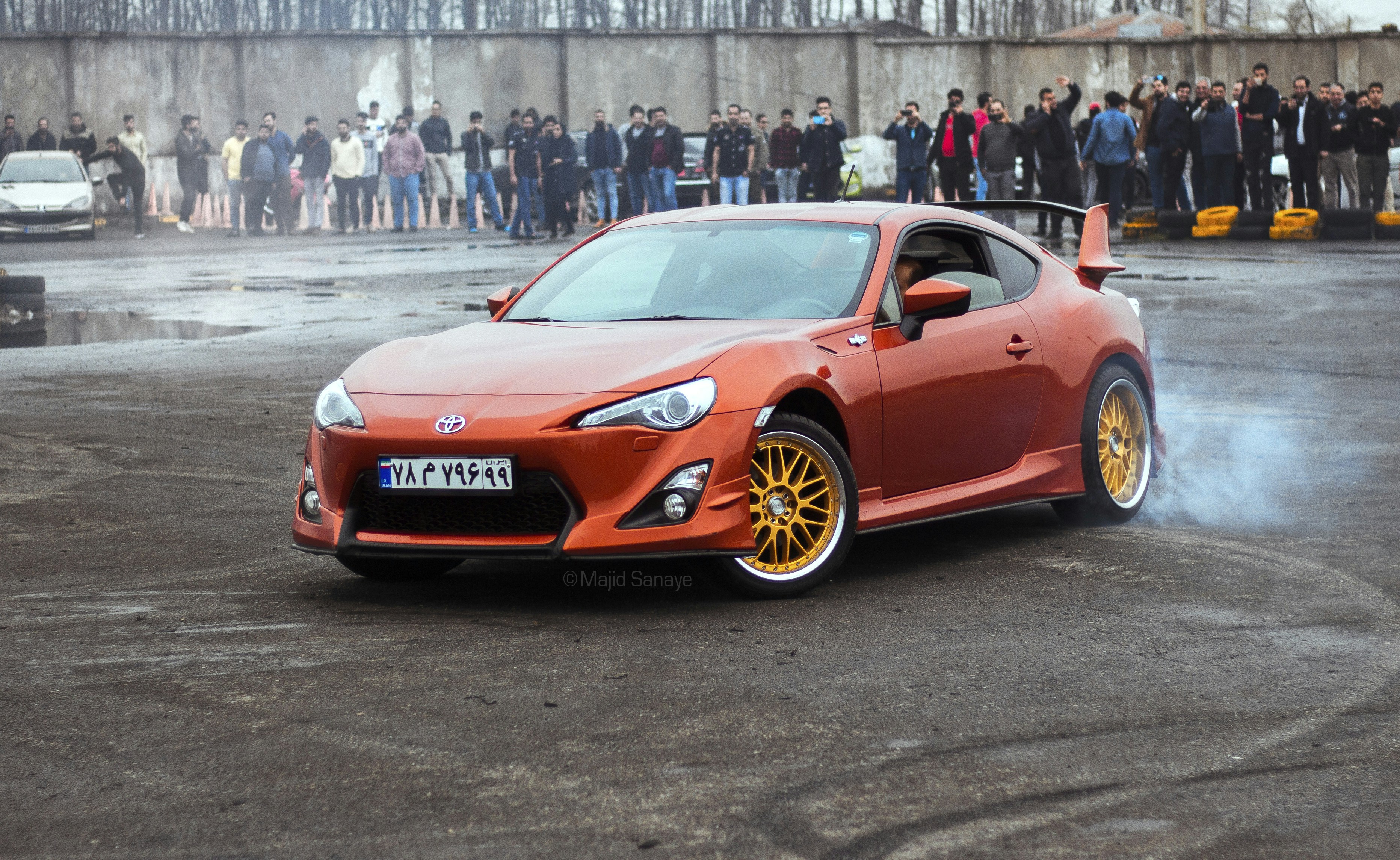 a red sports car with yellow rims on a parking lot
