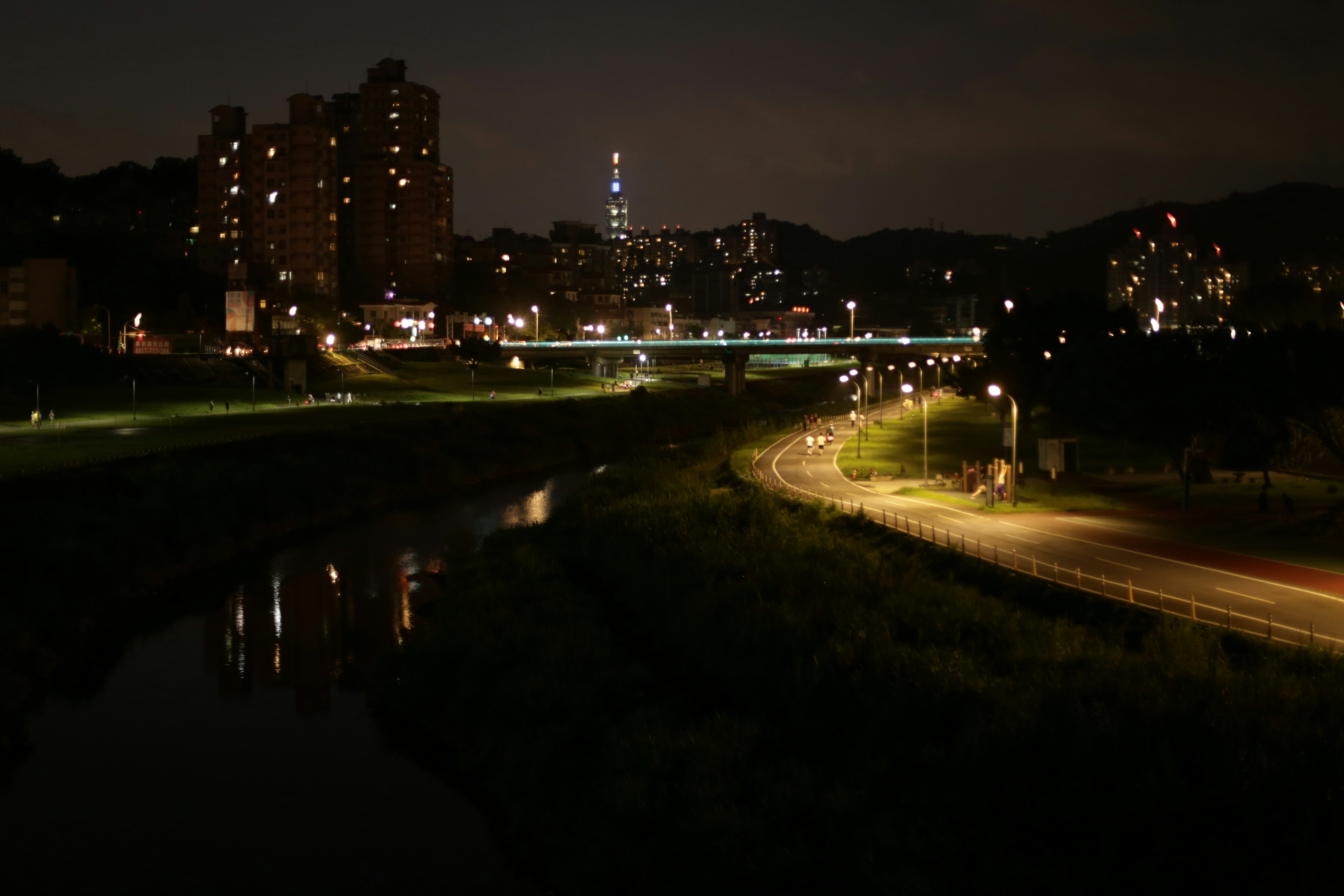 Nocturnal Arc: A Riverside Bridge Bathed in City Light