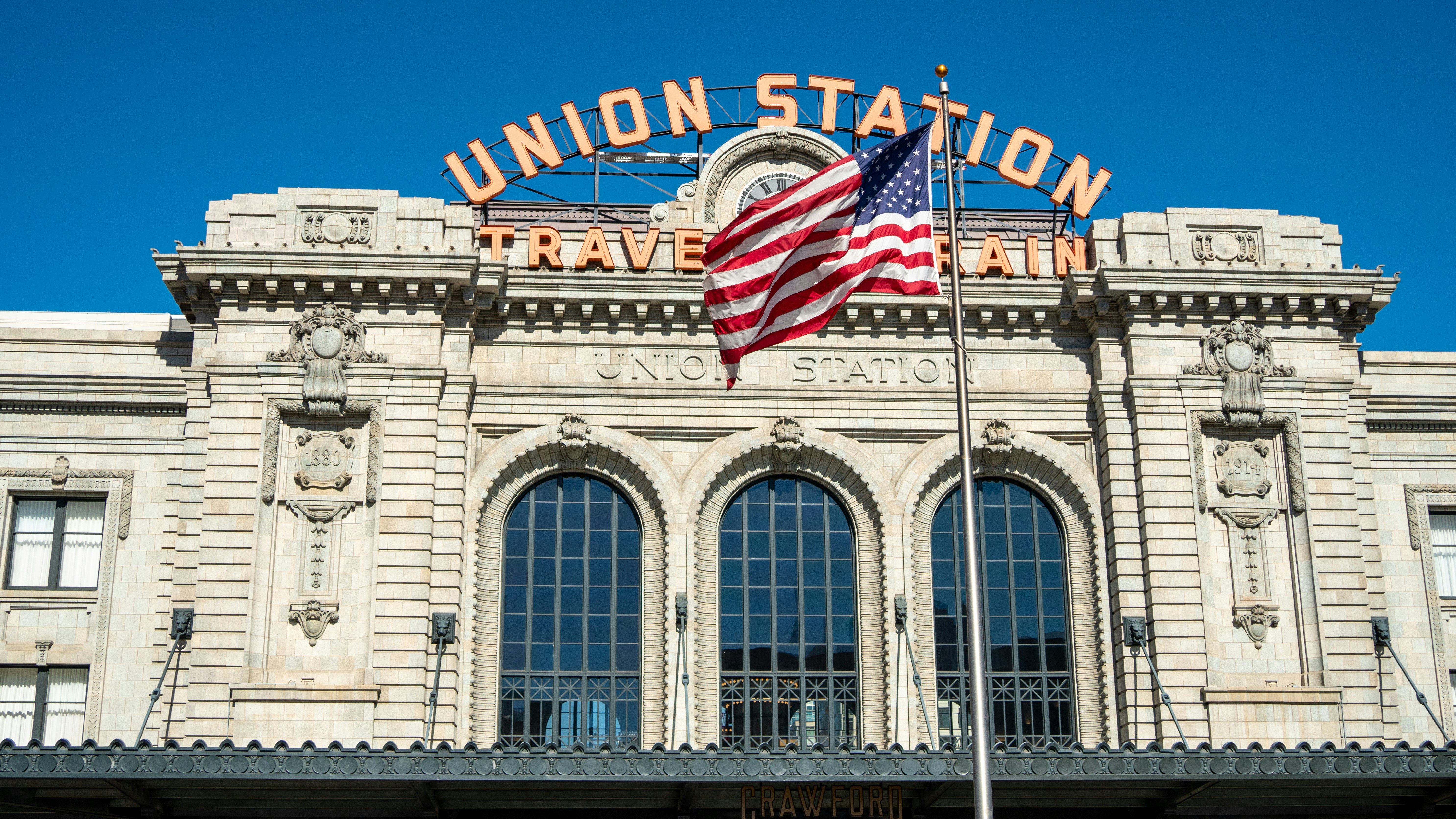 Historic Union Station facade showcasing intricate architectural details and an American flag waving in the foreground.