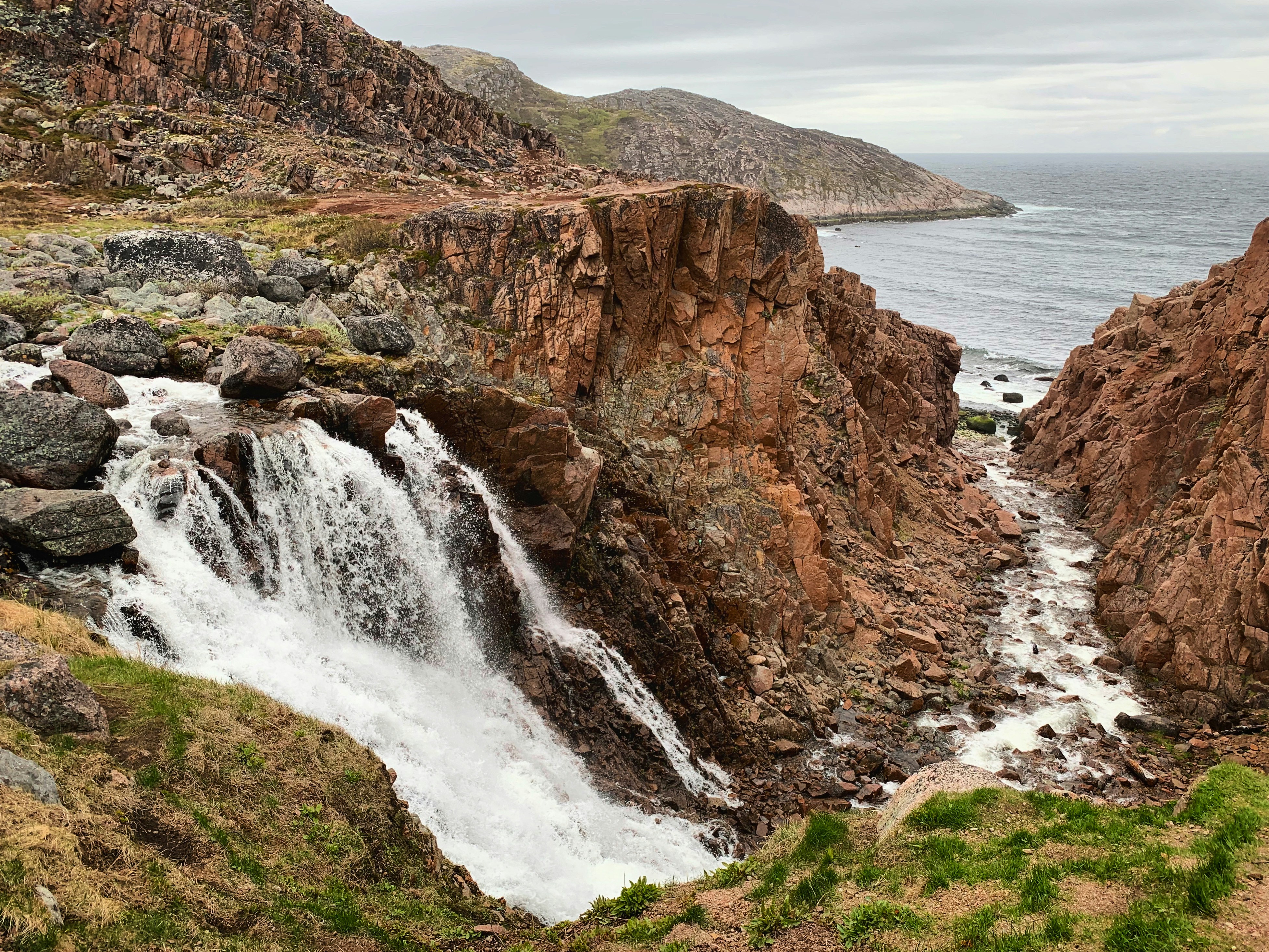 Scenic view of the waterfall flowing into the Arctic ocean against sky near Teriberka, Russia, June 2019