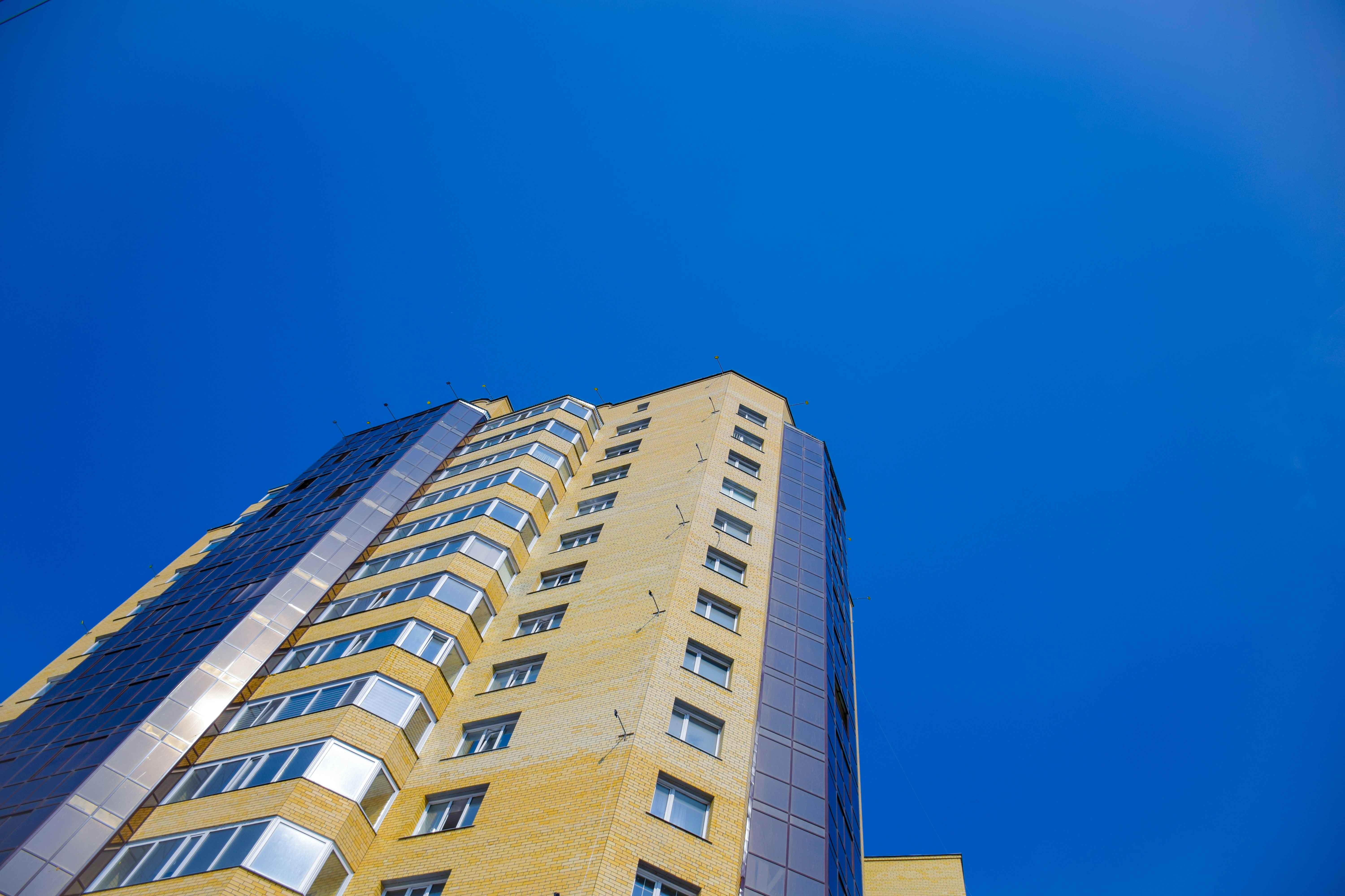 A tall yellow building with a blue sky in the background photo – Free ...