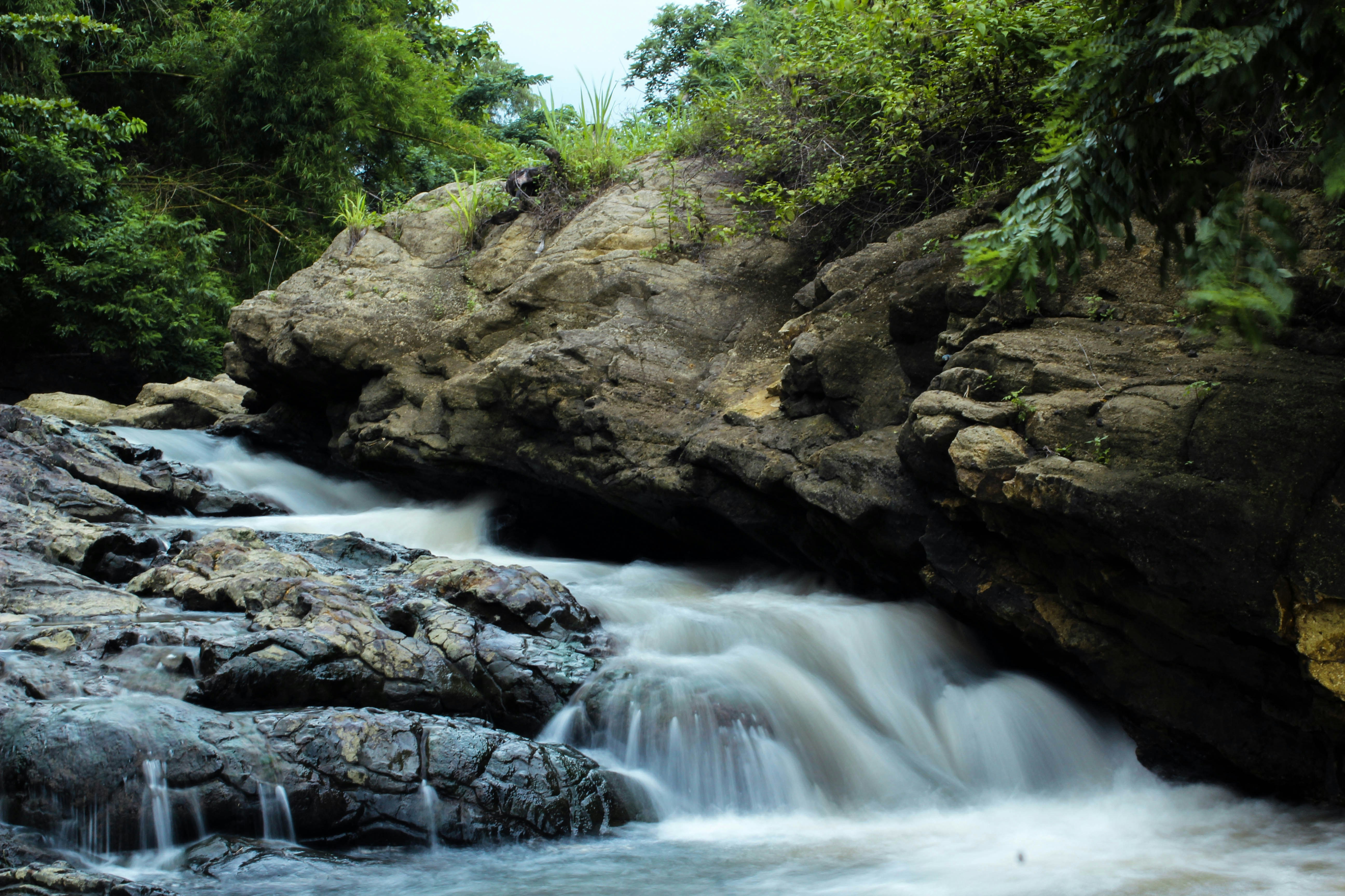 Silky smooth waterfall cascading over rugged rocks surrounded by lush greenery.