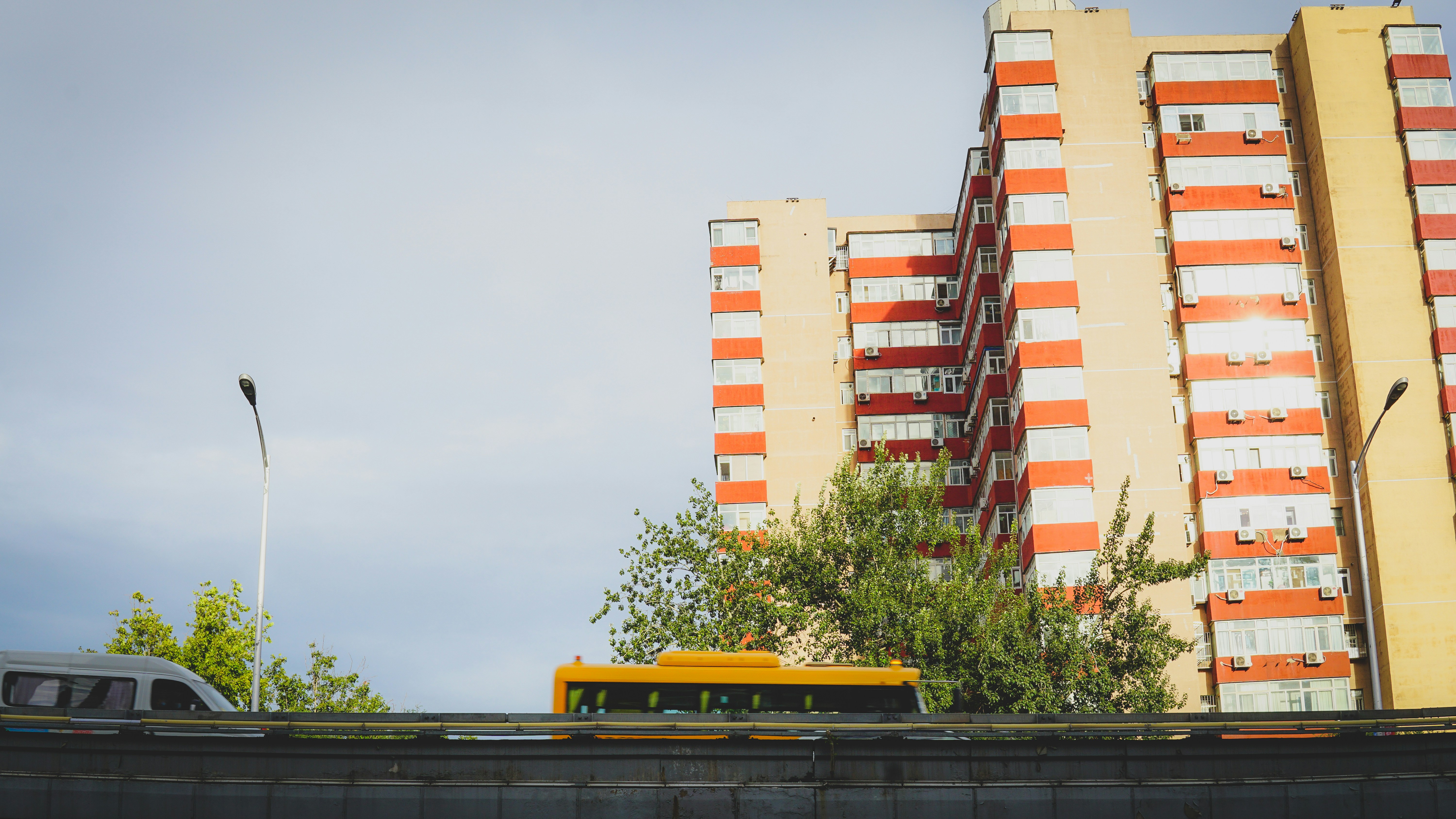 A yellow bus driving down a street next to tall buildings photo – Free ...