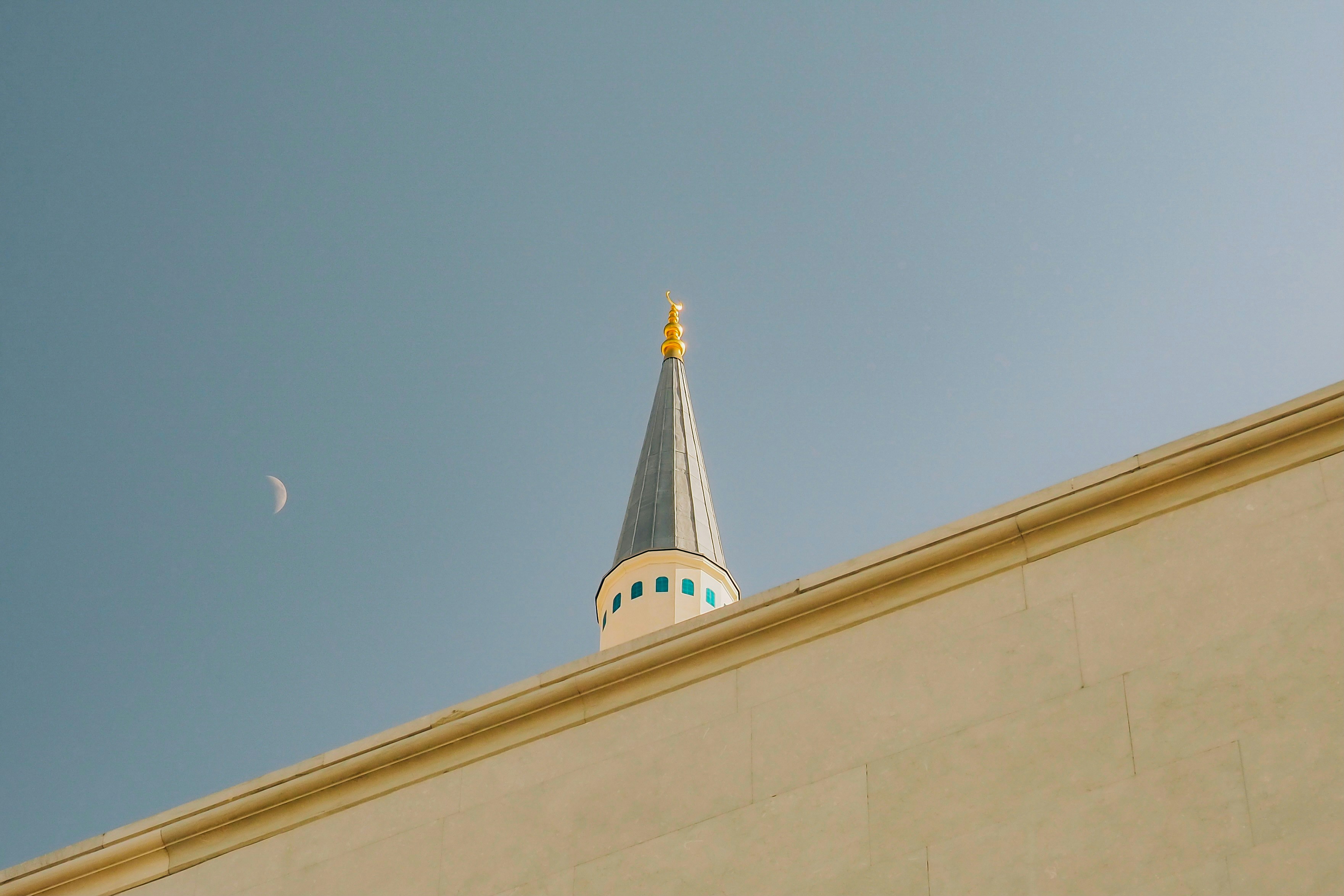 A building with a steeple and a half moon in the sky photo – Free ...