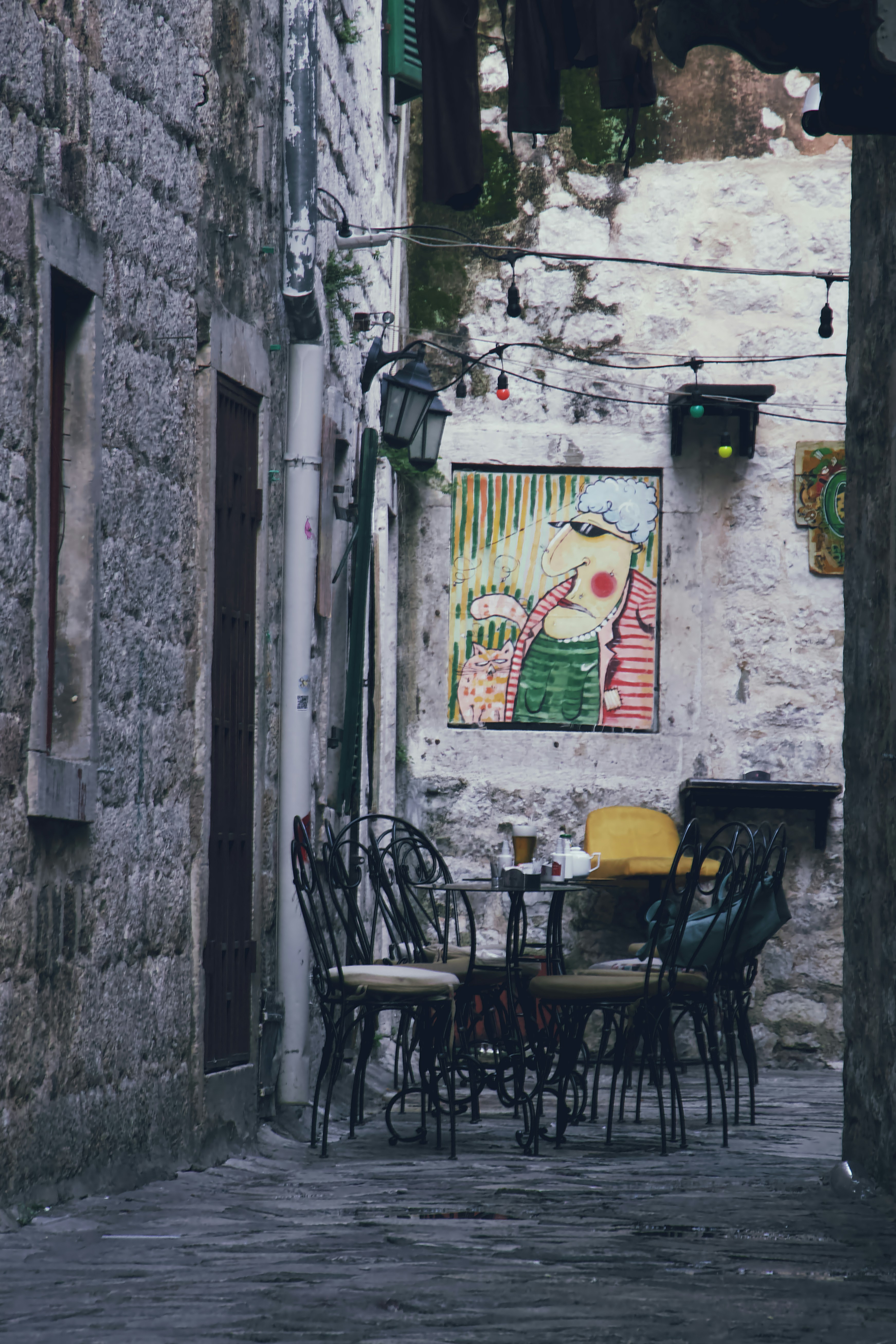Alleyway Café Portrait: A Cheery Mural Brightens a Cobblestone Alley