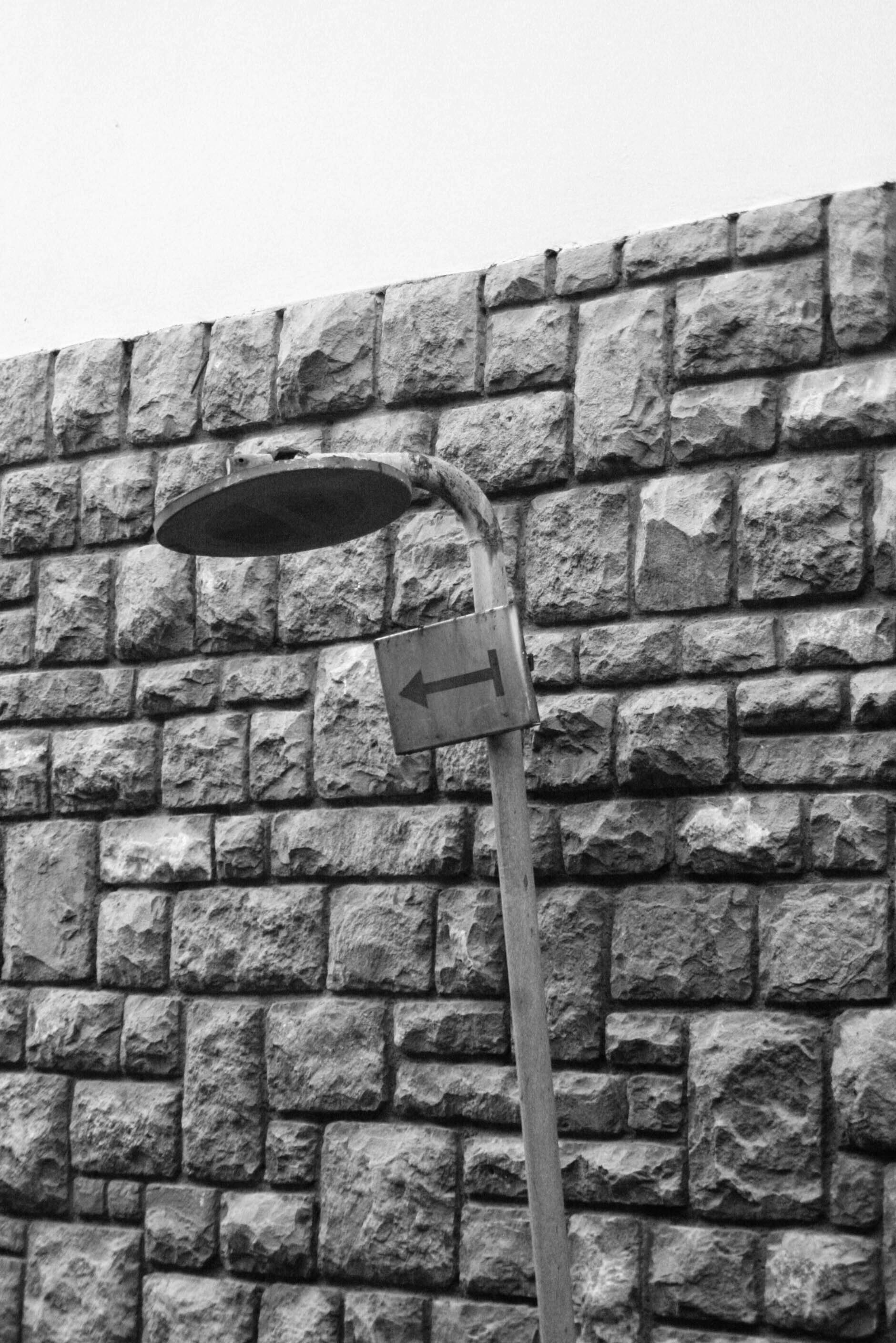 Curved Lamp Post Against Rough Stone Wall
