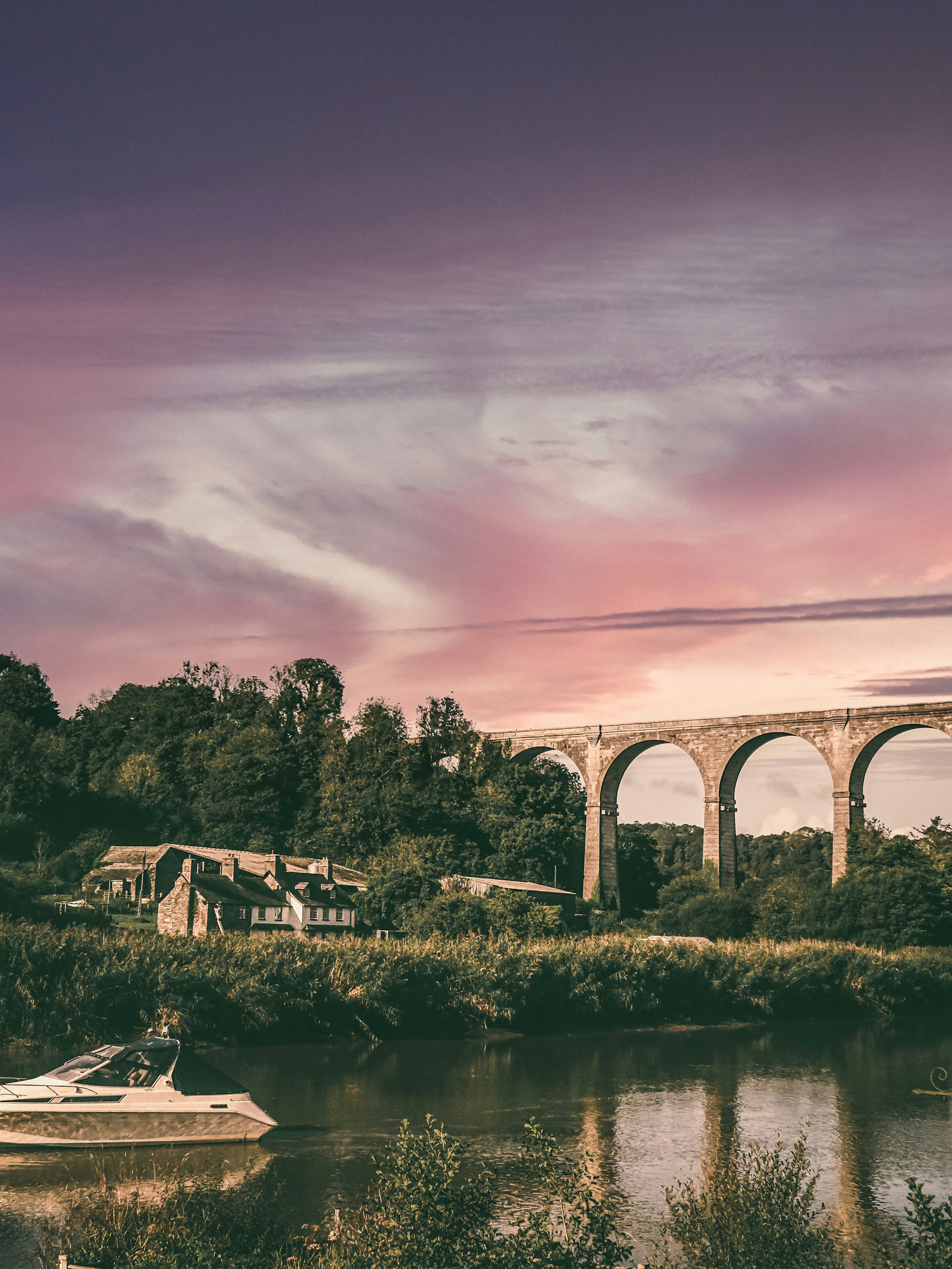 A boat floating on top of a river under a bridge photo – Free Calstock ...