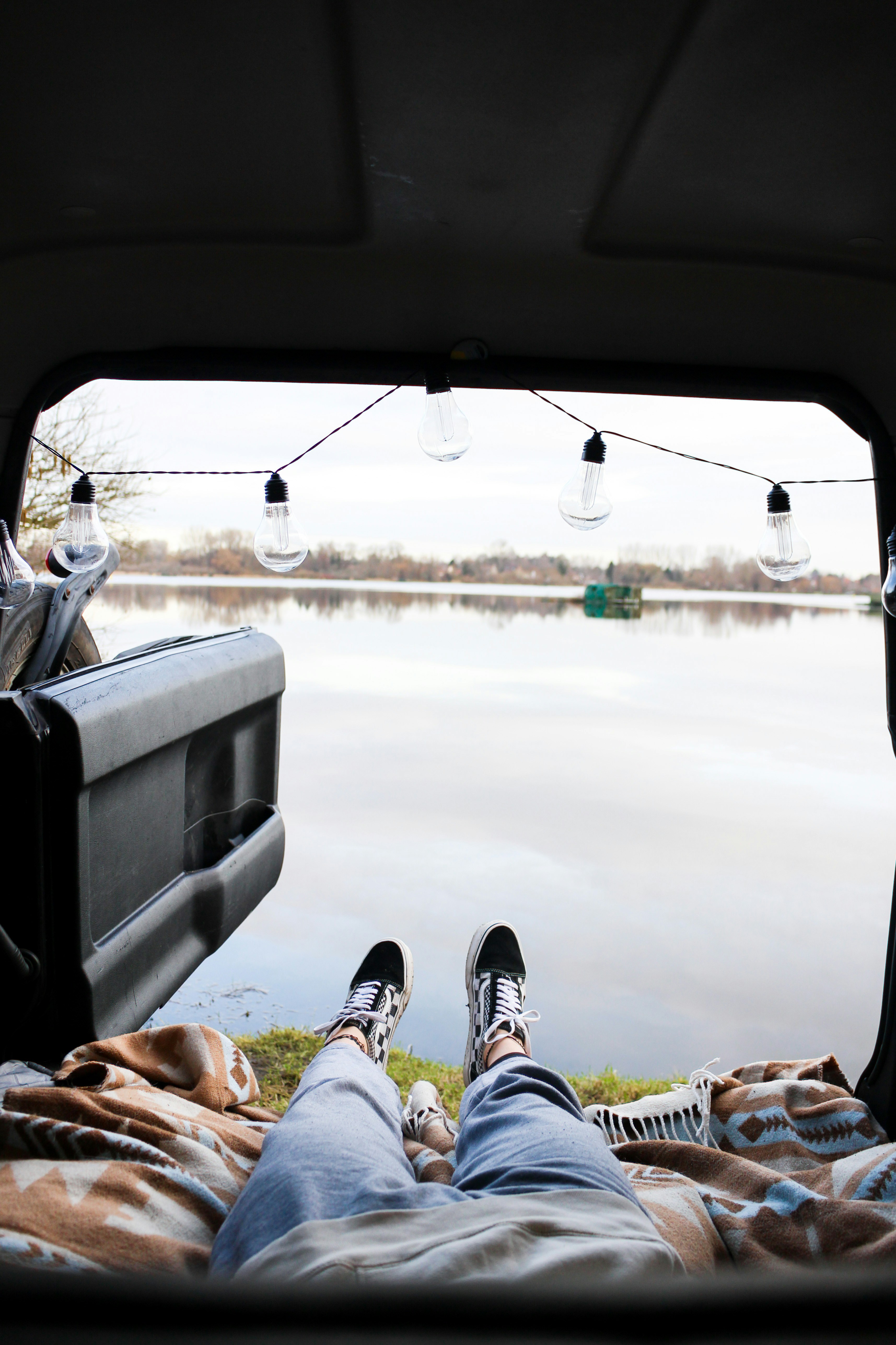 Horizon over reflections: a lakeside van-lounge under twinkle lights