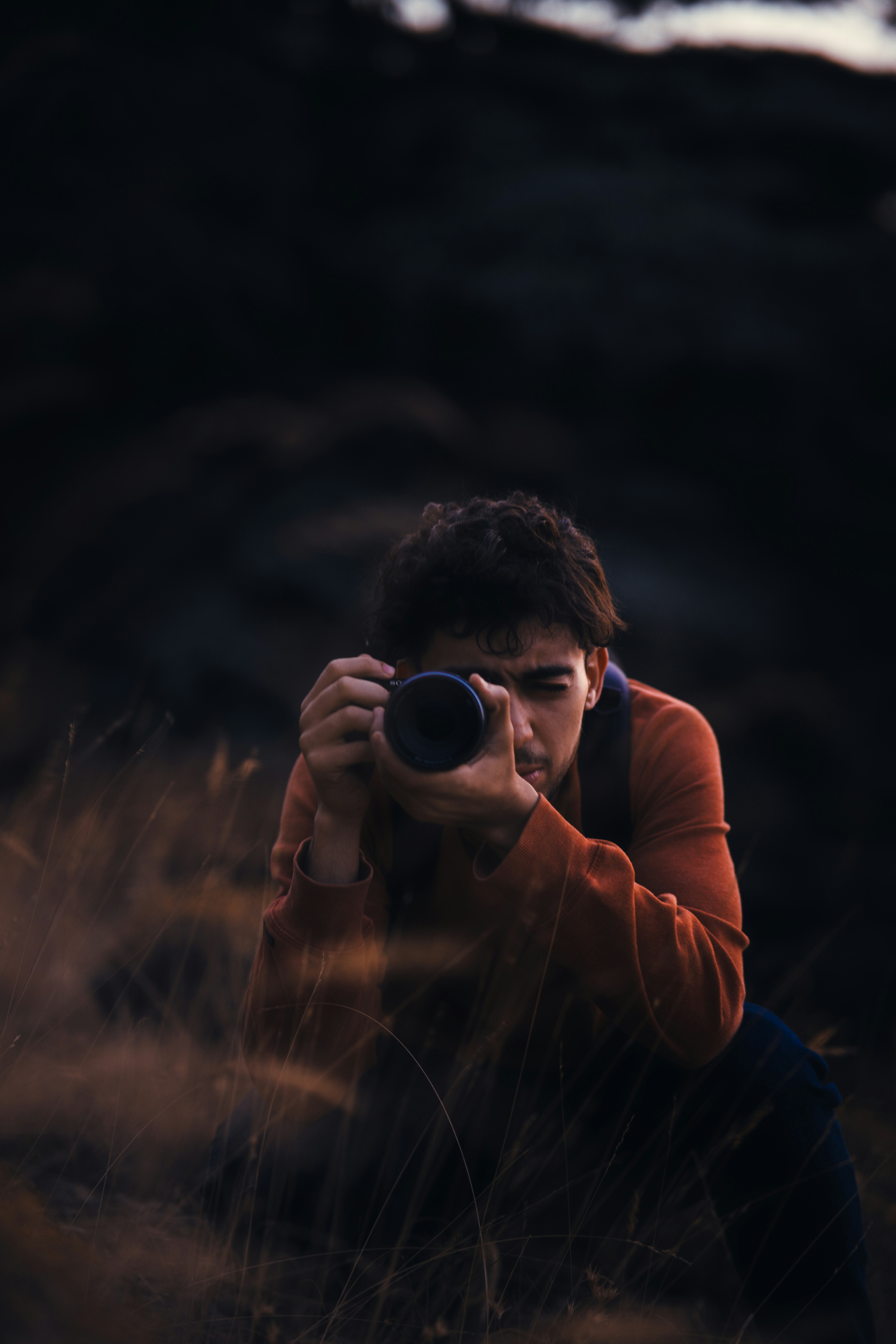 Dusk Focus: a photographer crouched in tall grass, chasing the moment through the lens