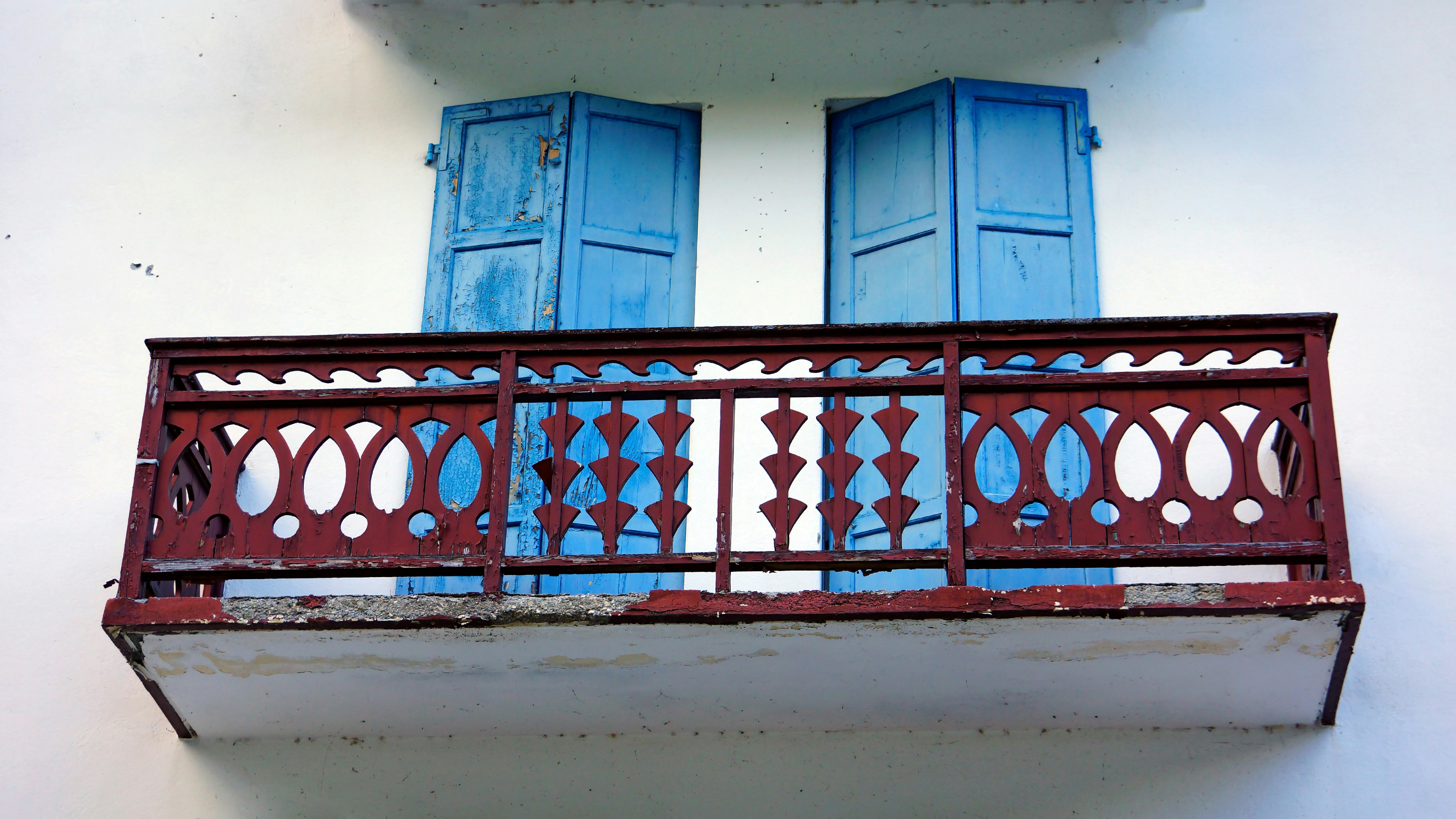 a balcony with two blue doors and a red railing