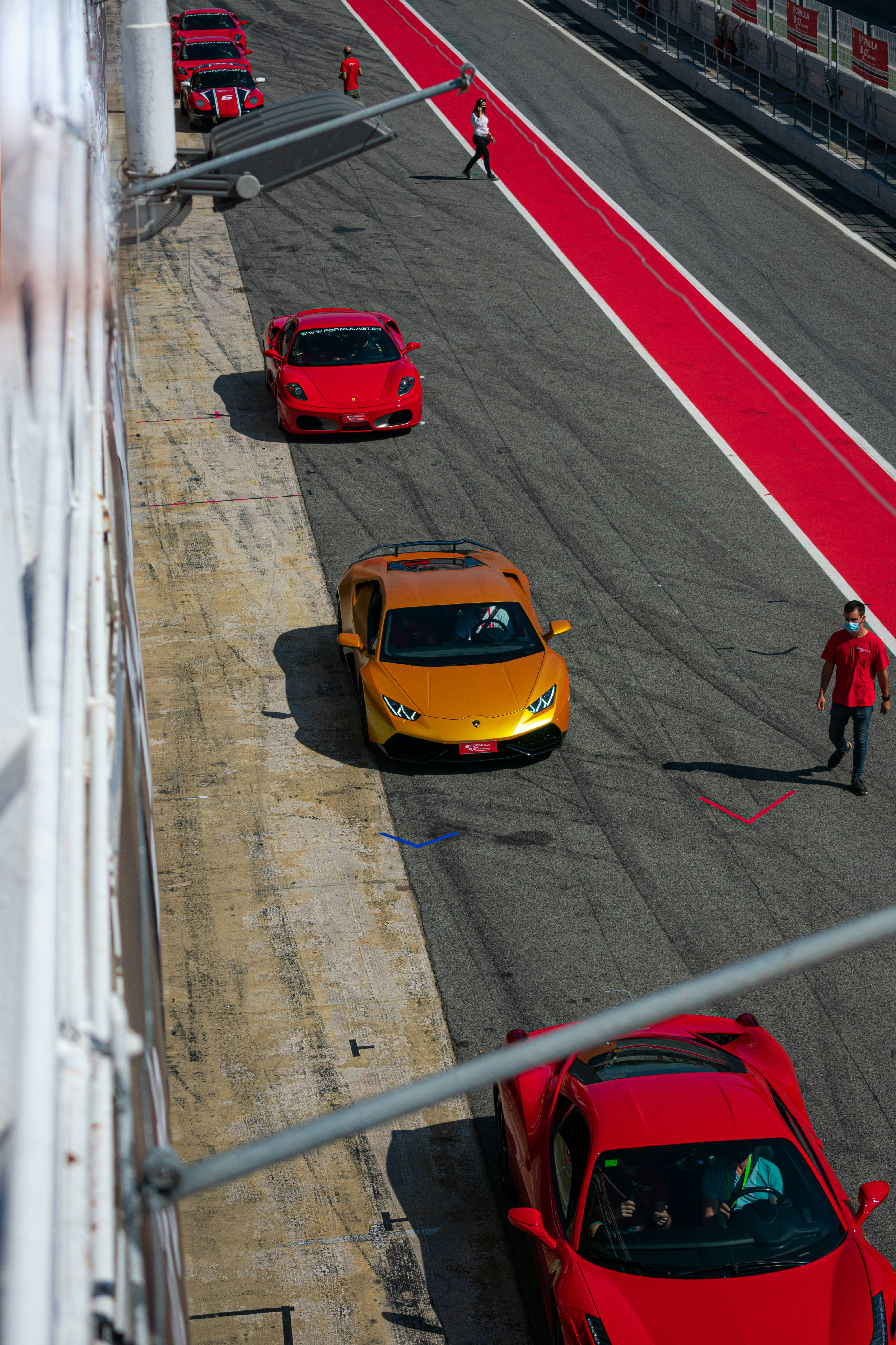 Chromatic Parade in the Pit Lane: A Yellow Fireball Among Reds