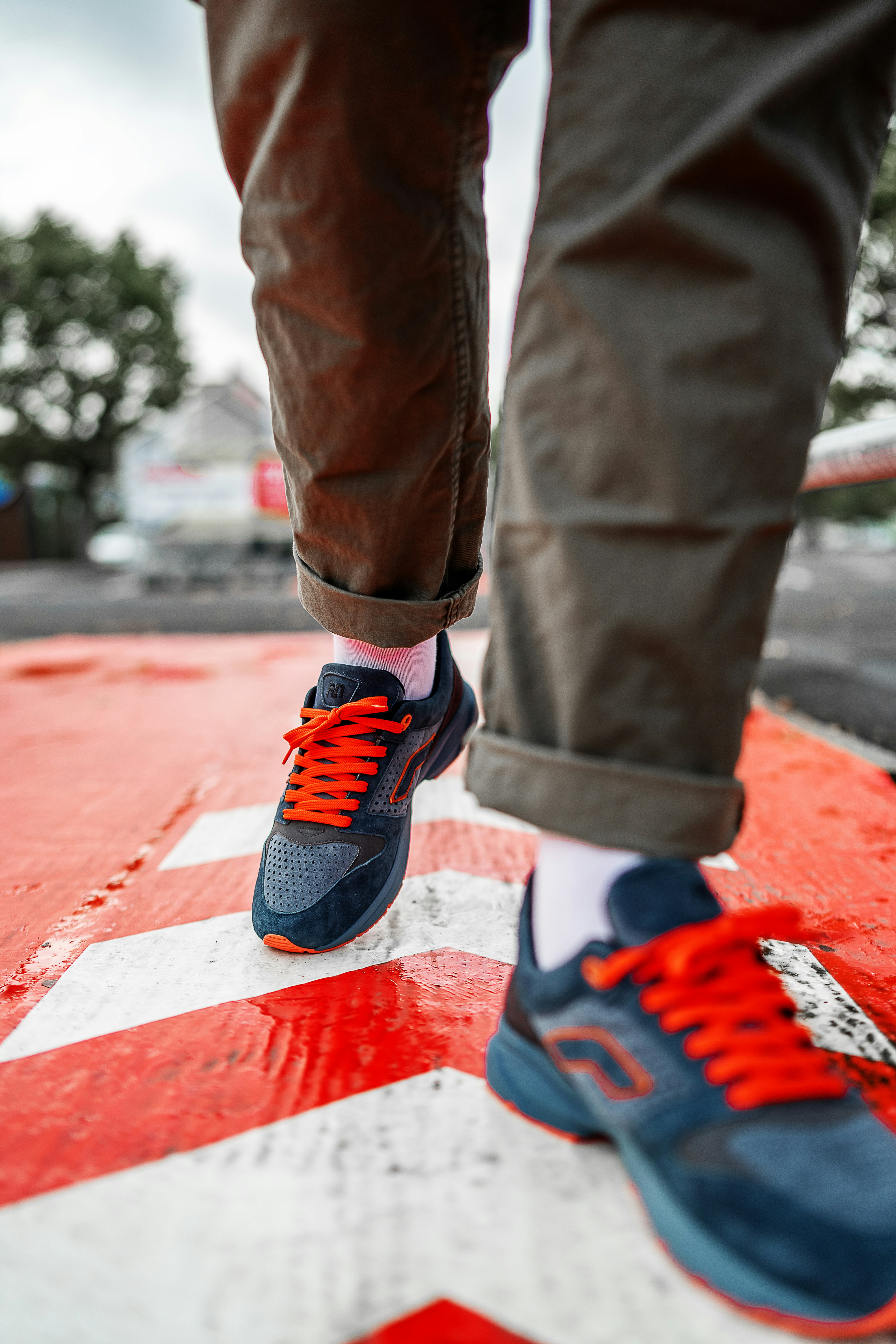 A person walking across a red and white cross walk photo – Free Sneaker ...