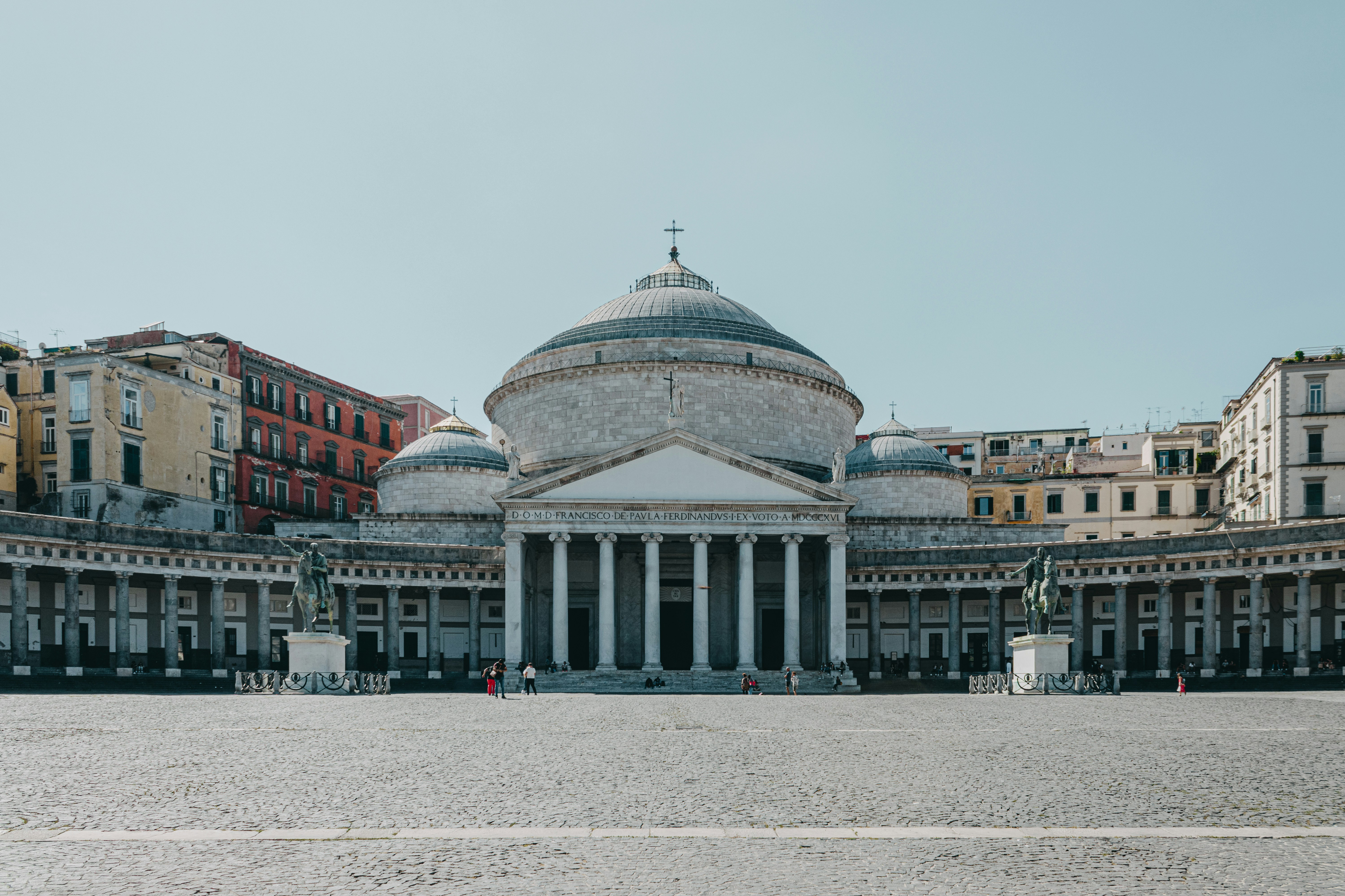 Grand neoclassical basilica with towering columns and a central dome under a clear blue sky.