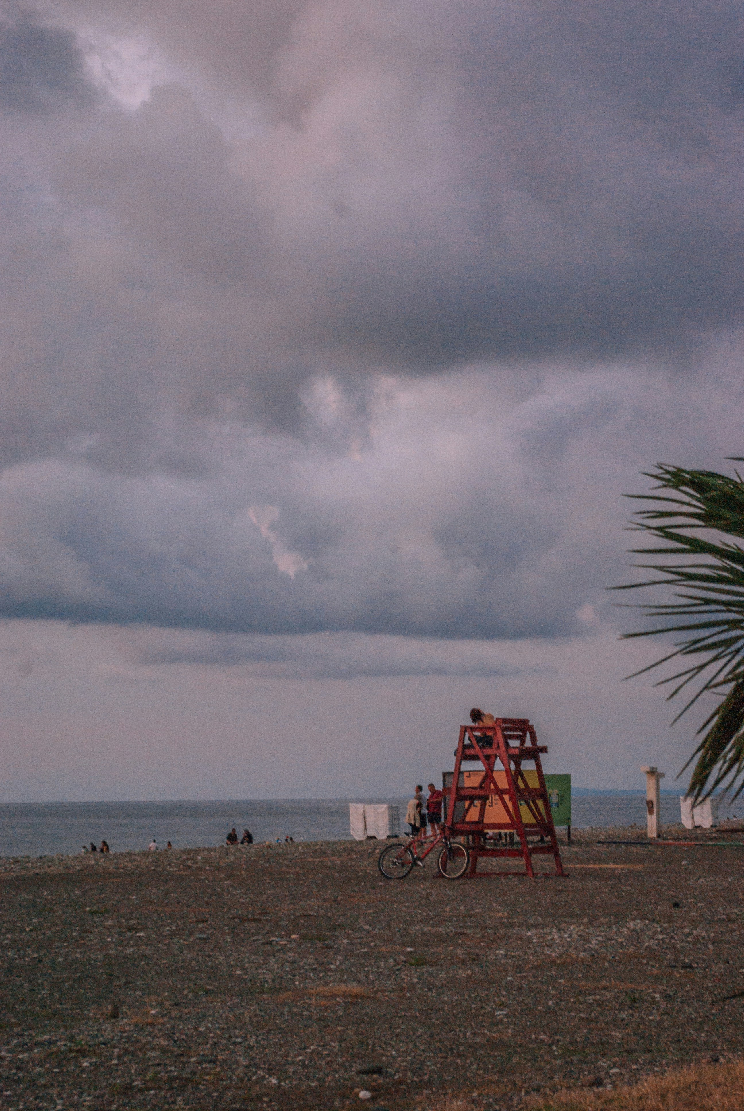 Crimson Lifeguard Chair Guards a Pebble Beach Under Stormy Skies