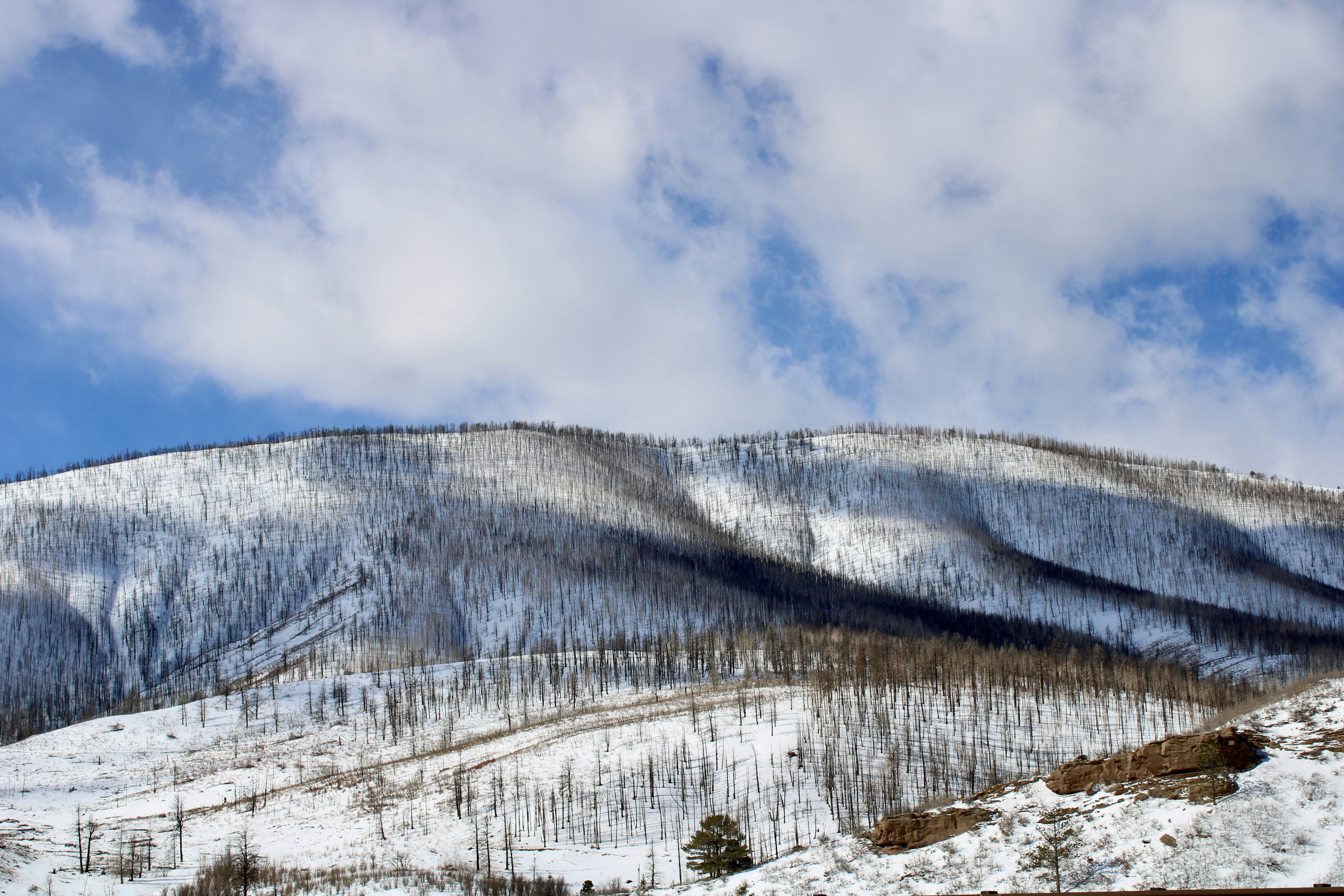 a mountain covered in snow under a cloudy blue sky