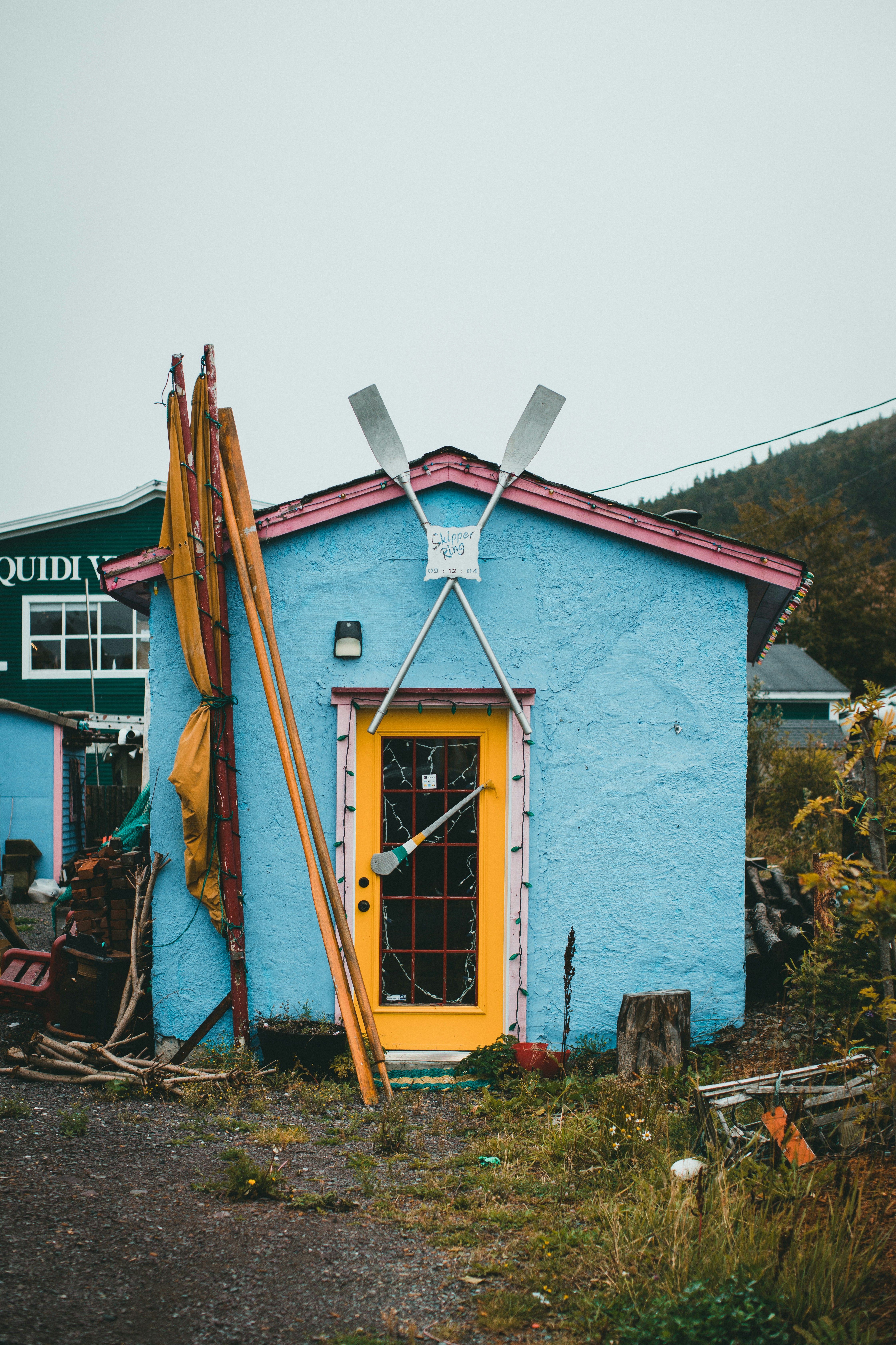 Coastal Blue Shed with Bright Yellow Door and Paddles